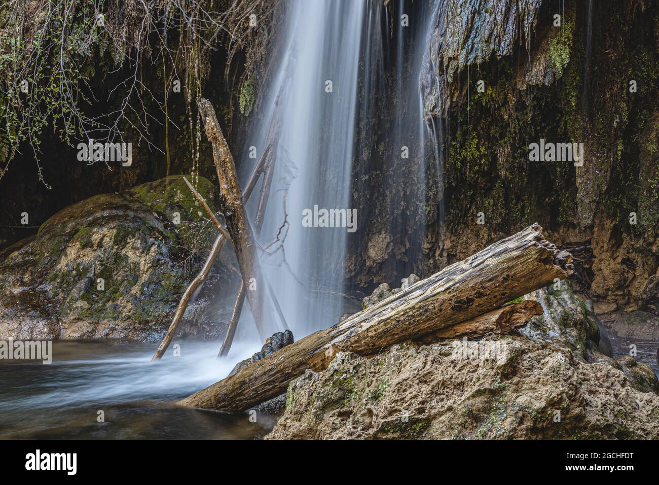 Beautiful fantastical waterfall with mossy cliffs and fallen logs in ...