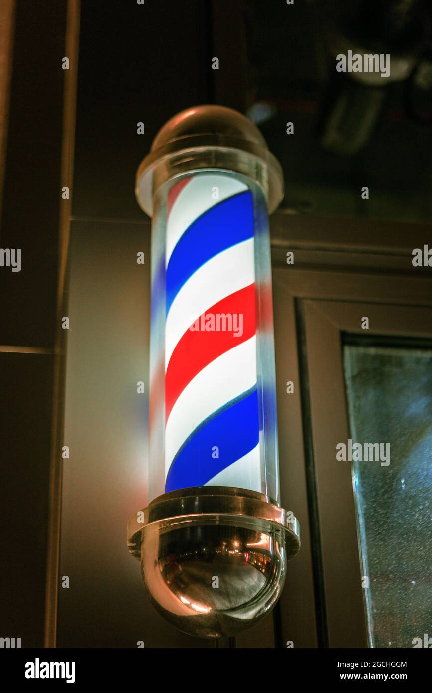 Barbershop pole sign attached to a wall of building Stock Photo - Alamy
