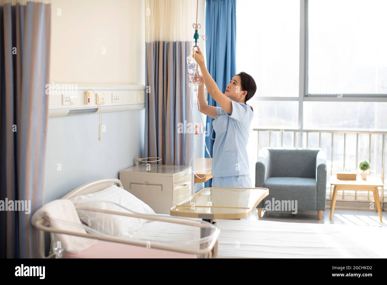 Young nurse checking IV drip in hospital ward Stock Photo - Alamy