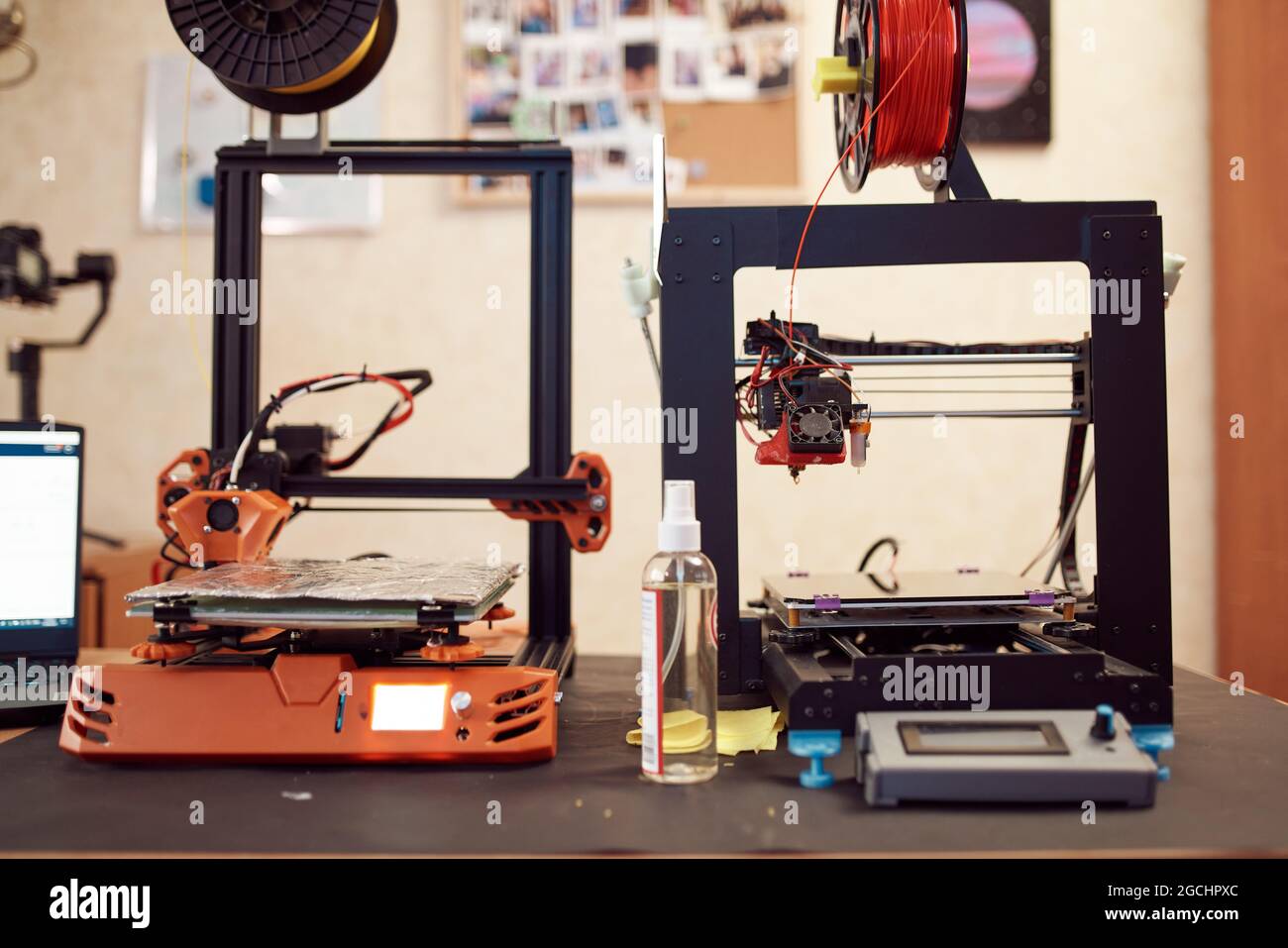 Modern 3D printers with plastic coil placed on table near laptop in ...