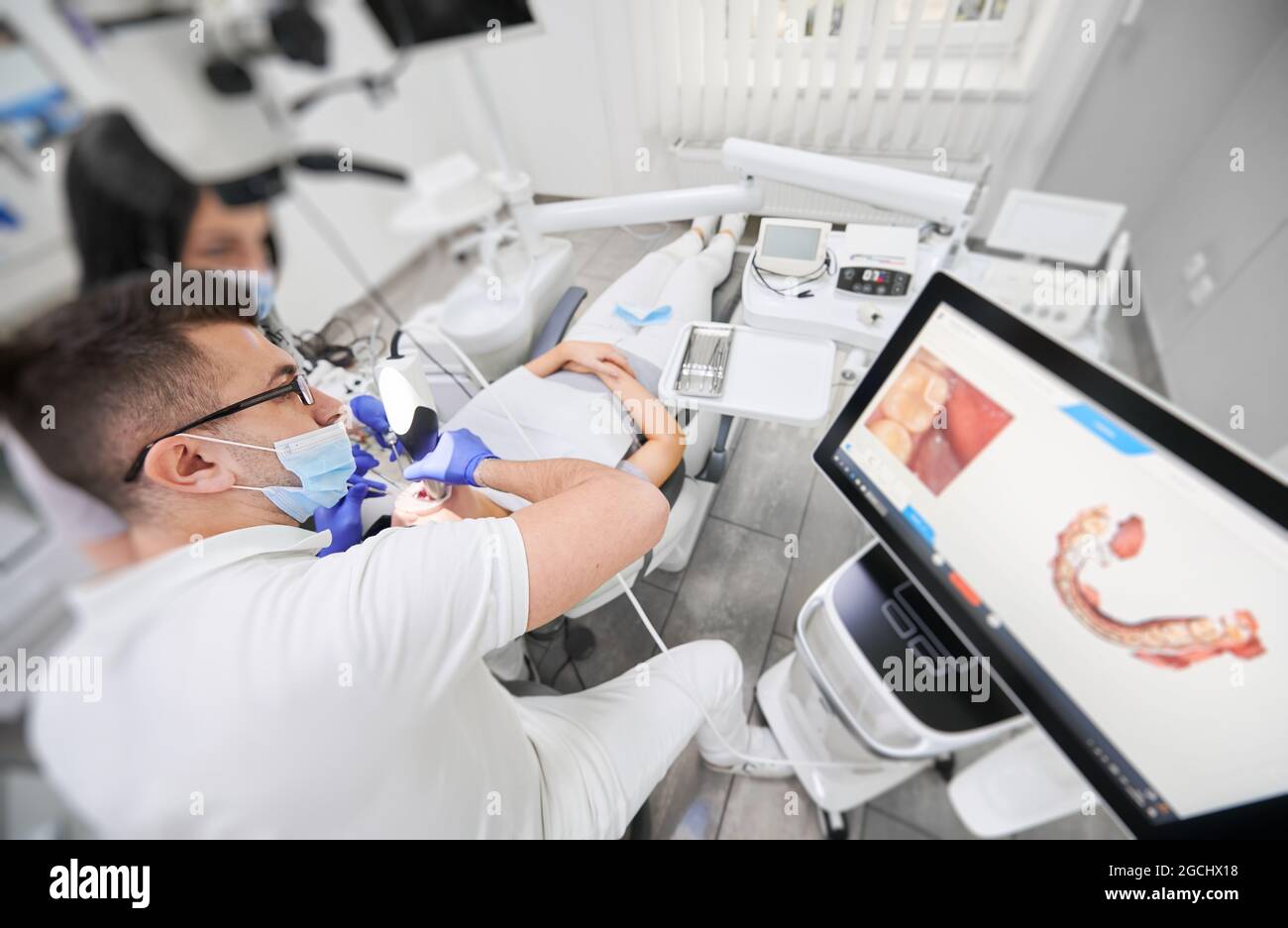 Dentist and assistant in medical masks using dental intraoral scanner ...