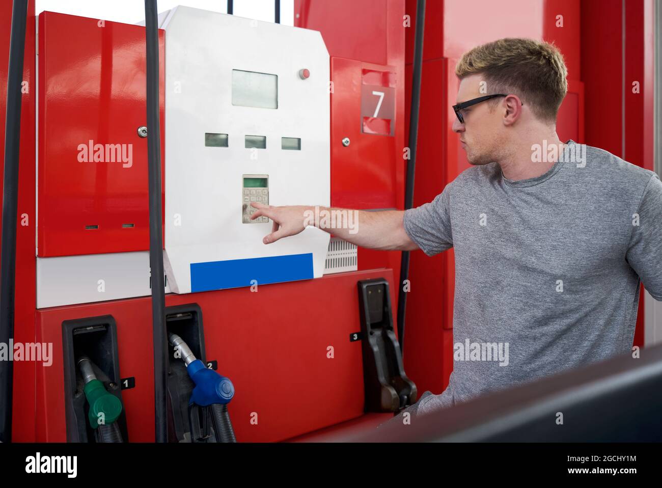 Young caucasian driver with sunglass, pressing the number on refueling ...