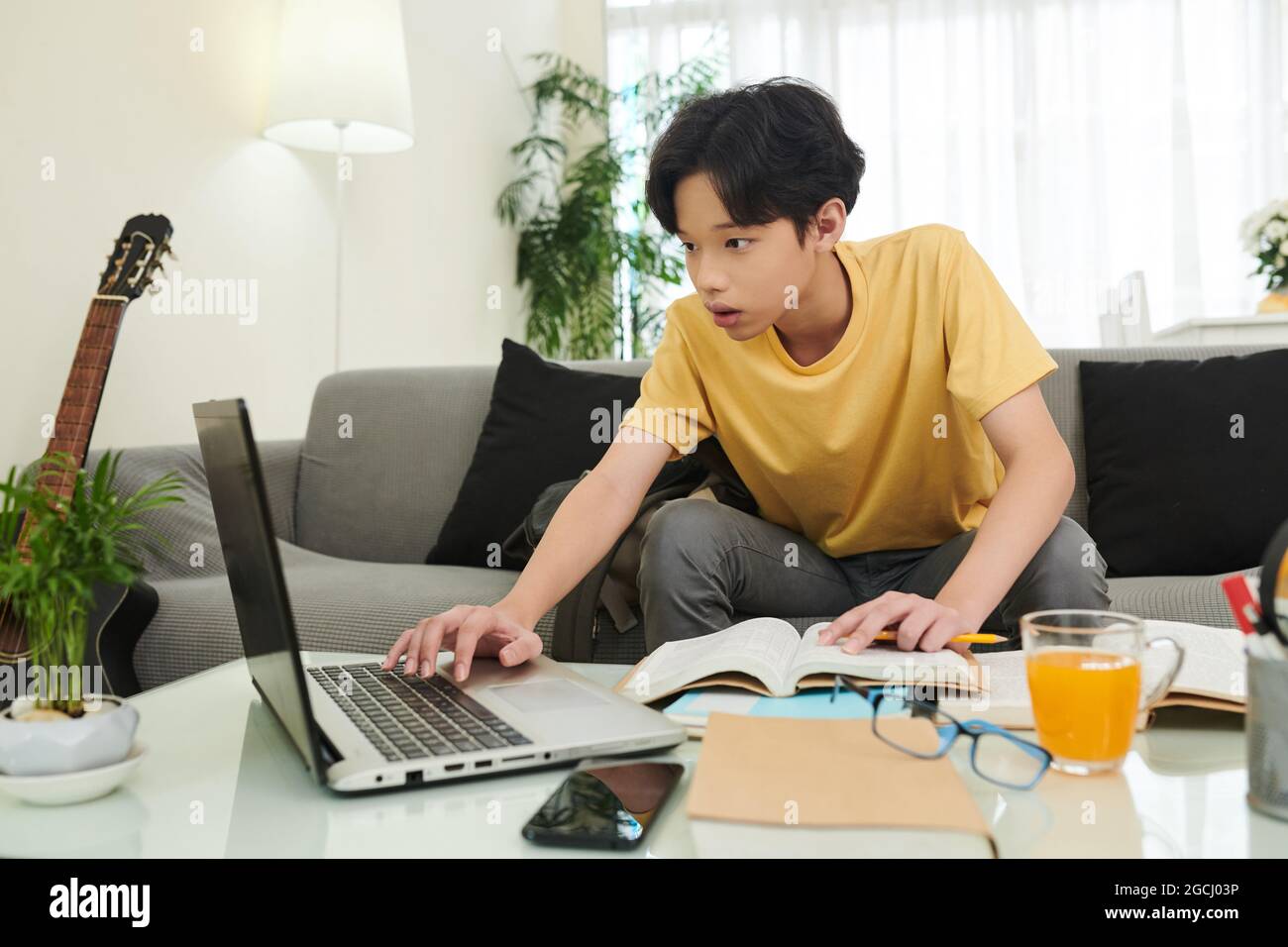 Teenage schoolboy doing homework, he is searching for information for ...