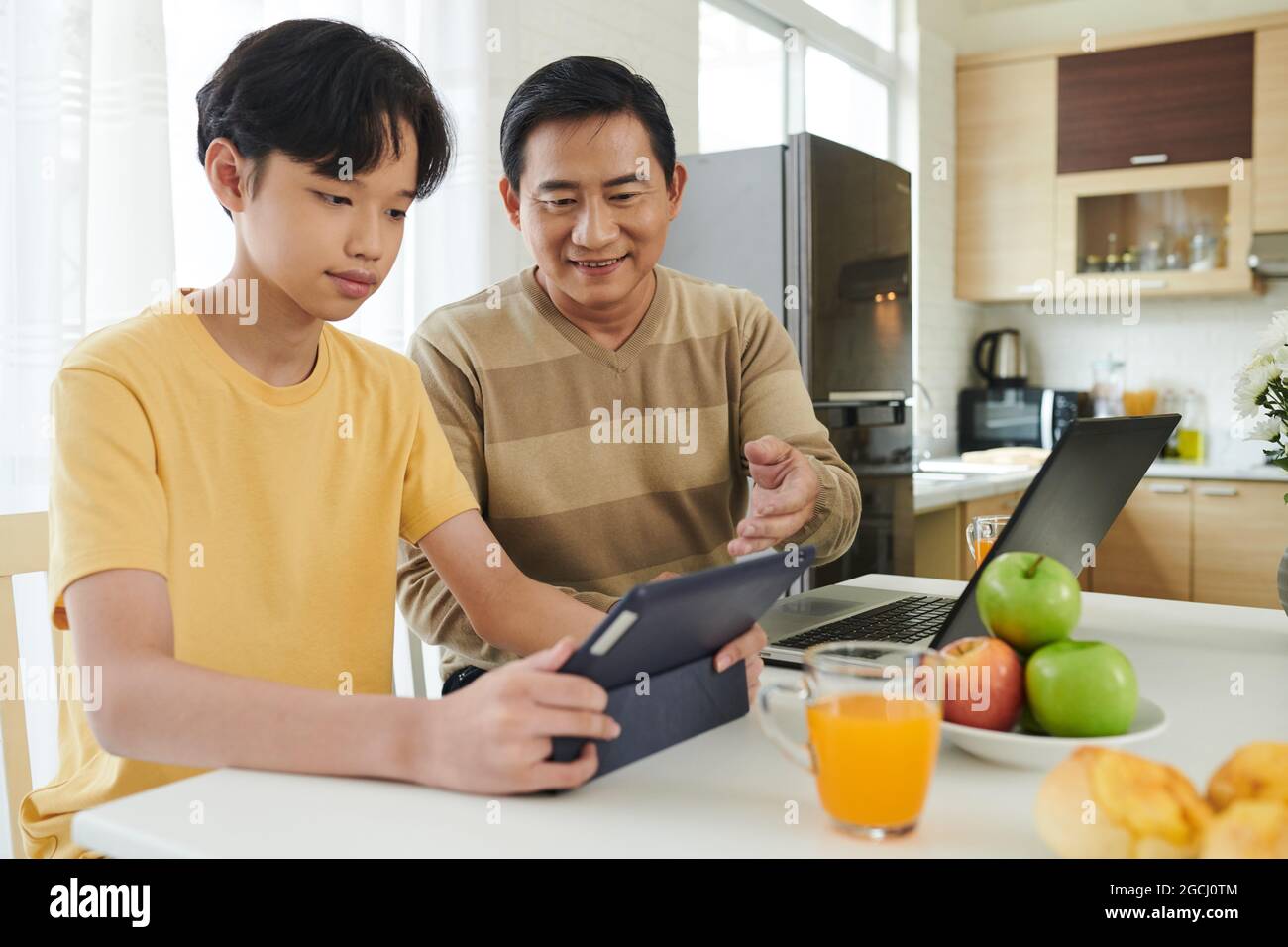 Smiling father helping his teenage son with installing educational ...