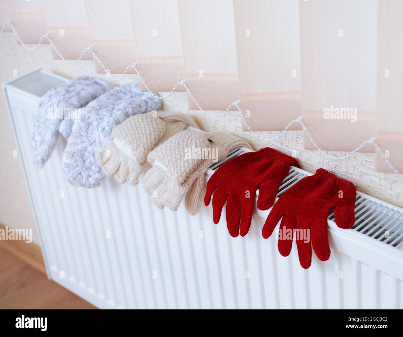 Knitted gloves drying on heating radiator Stock Photo - Alamy