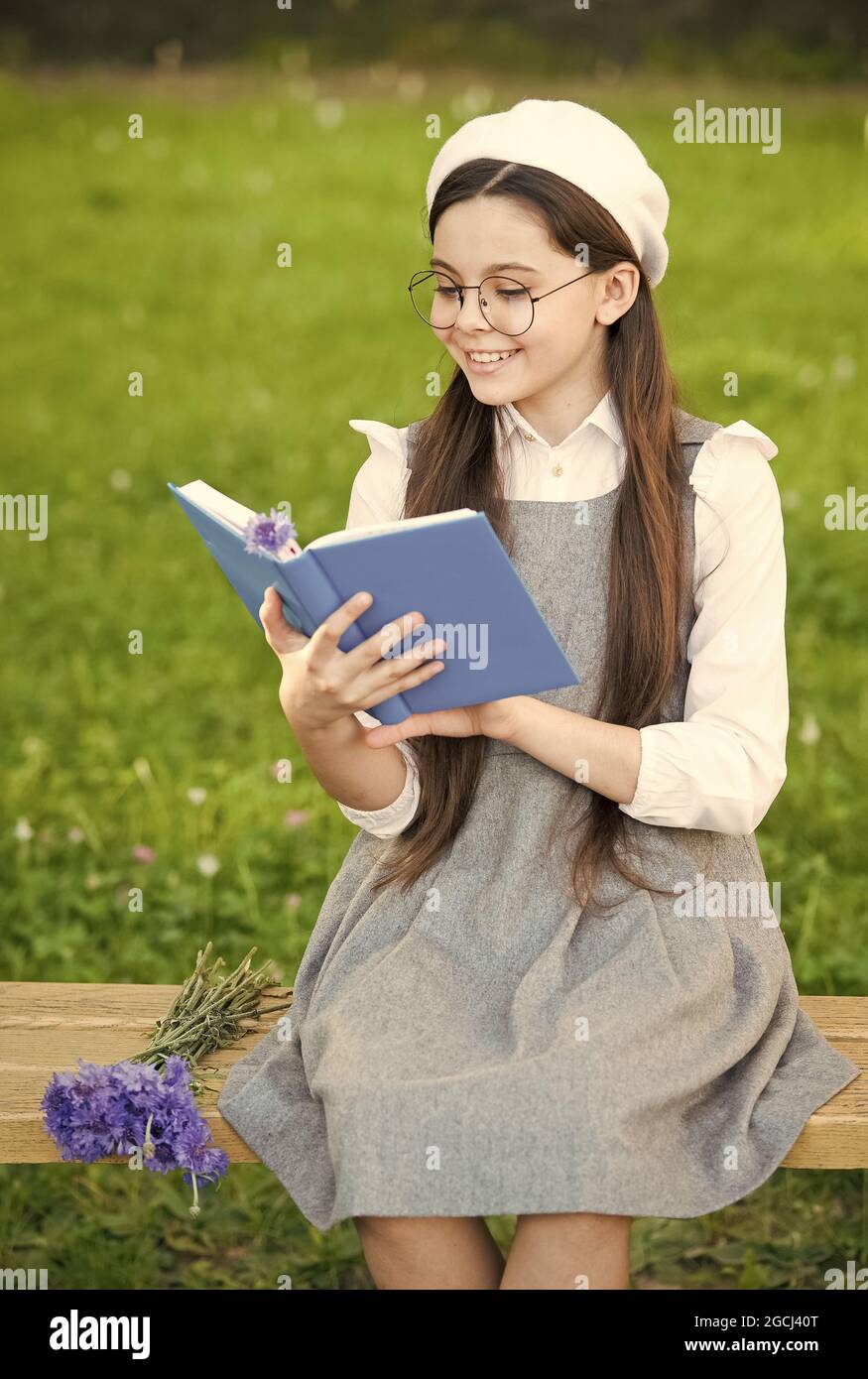Elegant schoolgirl child girl reading book in park, french language ...