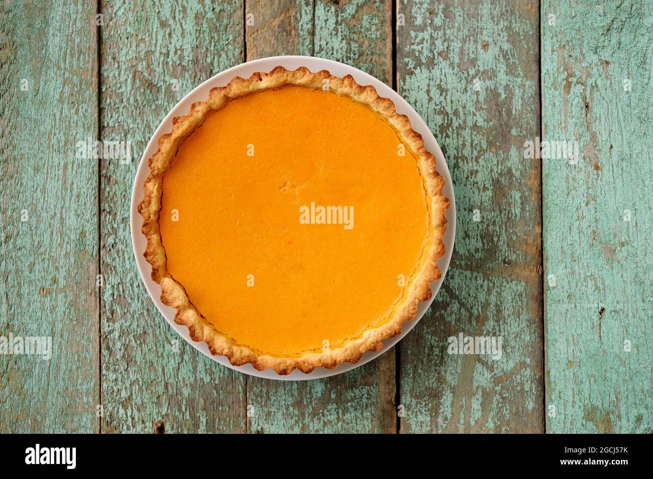 Homemade oldfashioned open round pumpkin pie on old painted wood table ...