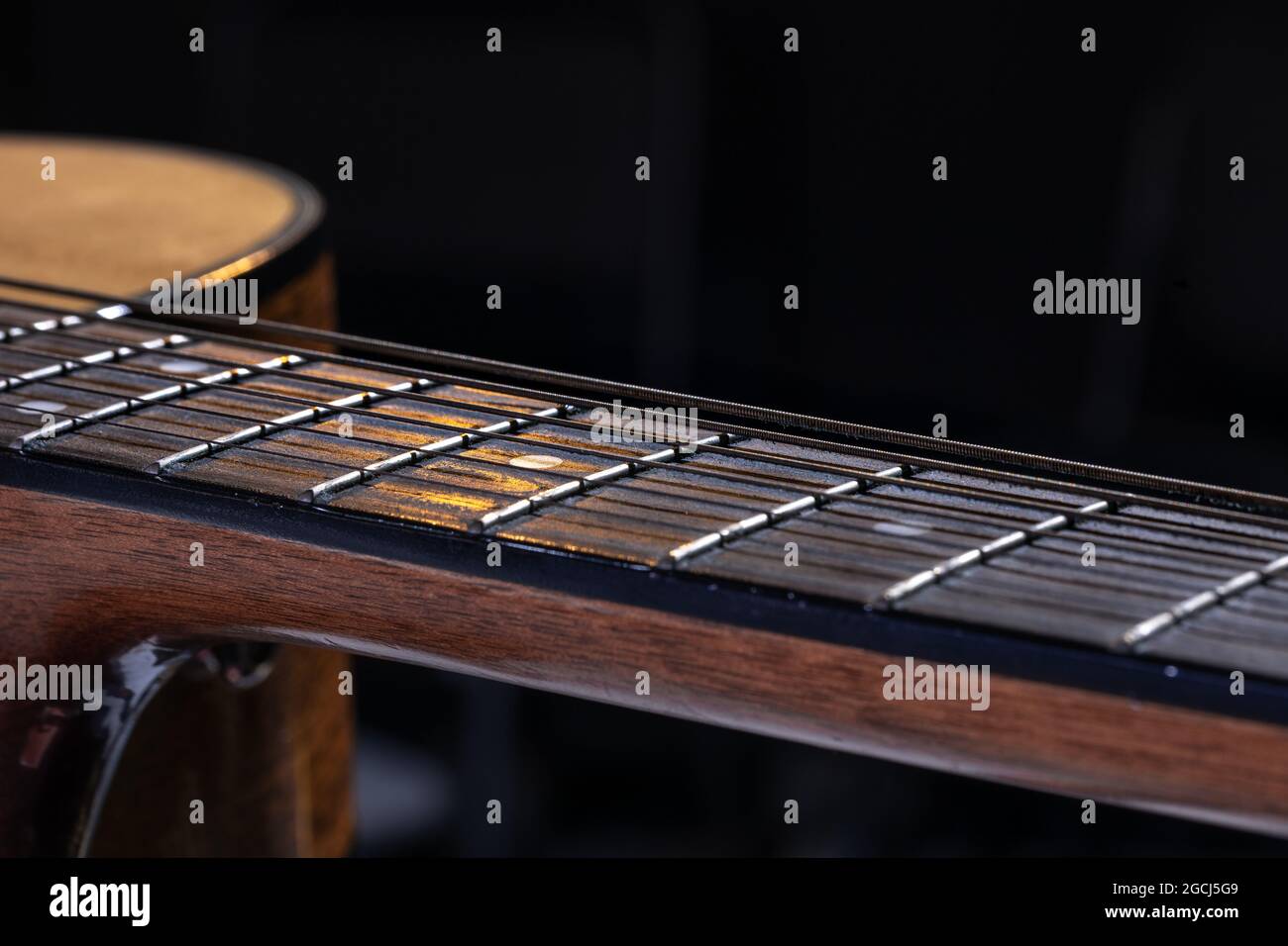Part of an acoustic guitar, guitar fretboard with strings on a black ...