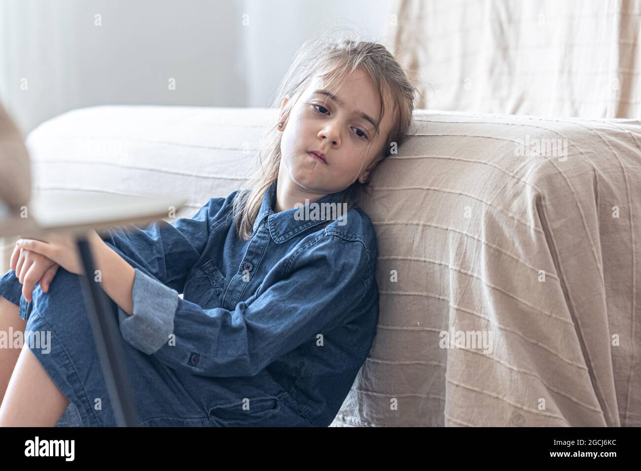 A tired little girl is sitting in a room on the floor Stock Photo - Alamy
