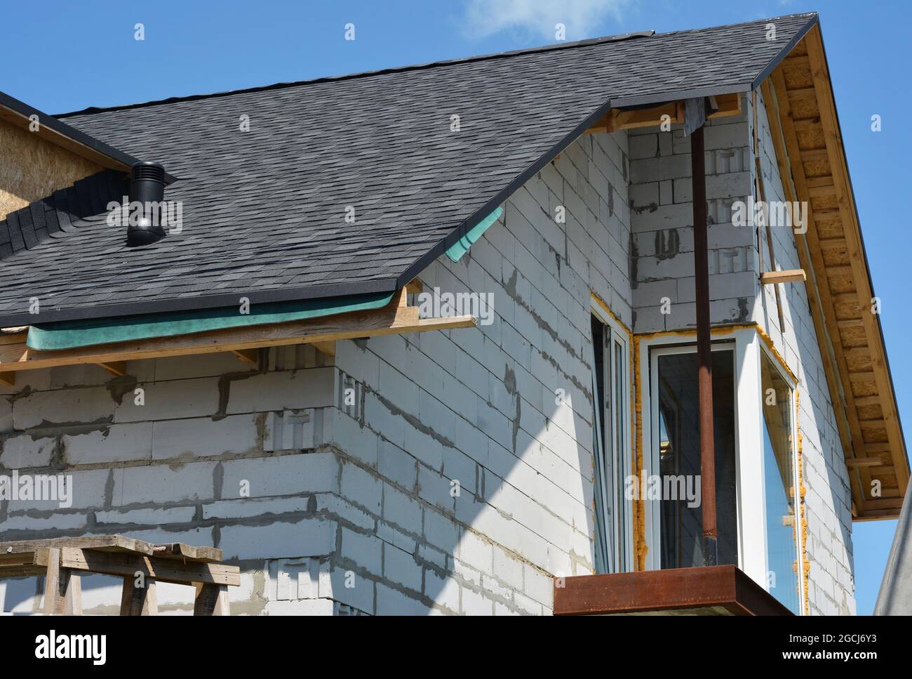 A brick house under construction with a roof covered with asphalt ...