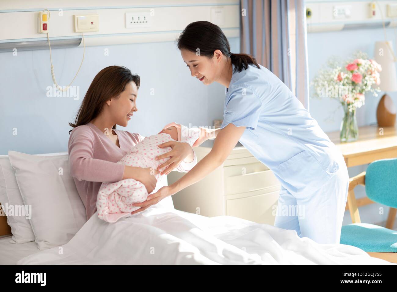 Female nurse handing newborn baby to mother in hospital ward Stock ...