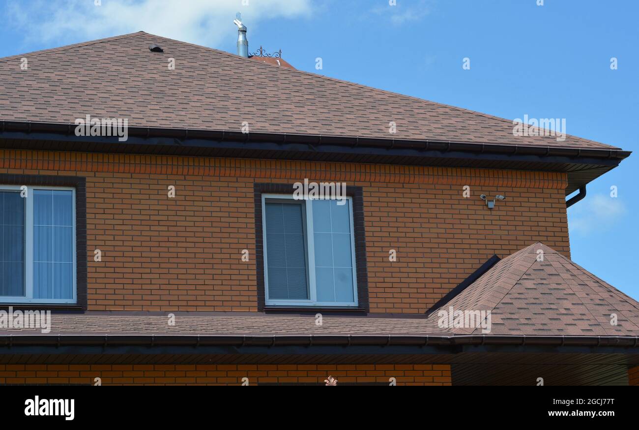 A close-up of a house with an asphalt shingled roofing construction, a ...