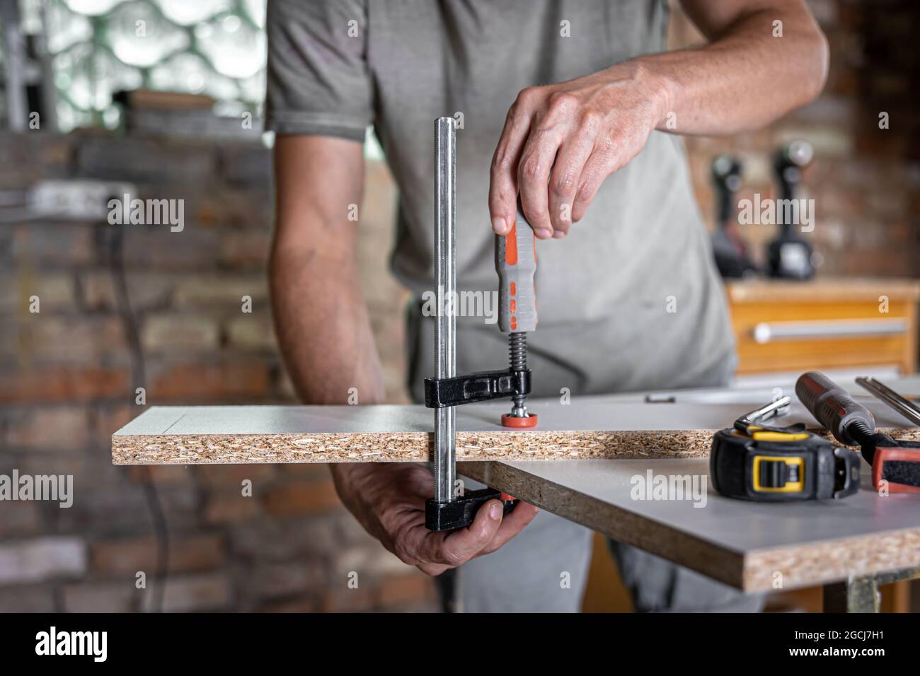 Carpenter doing wood work using clamping hand tool in his workshop ...