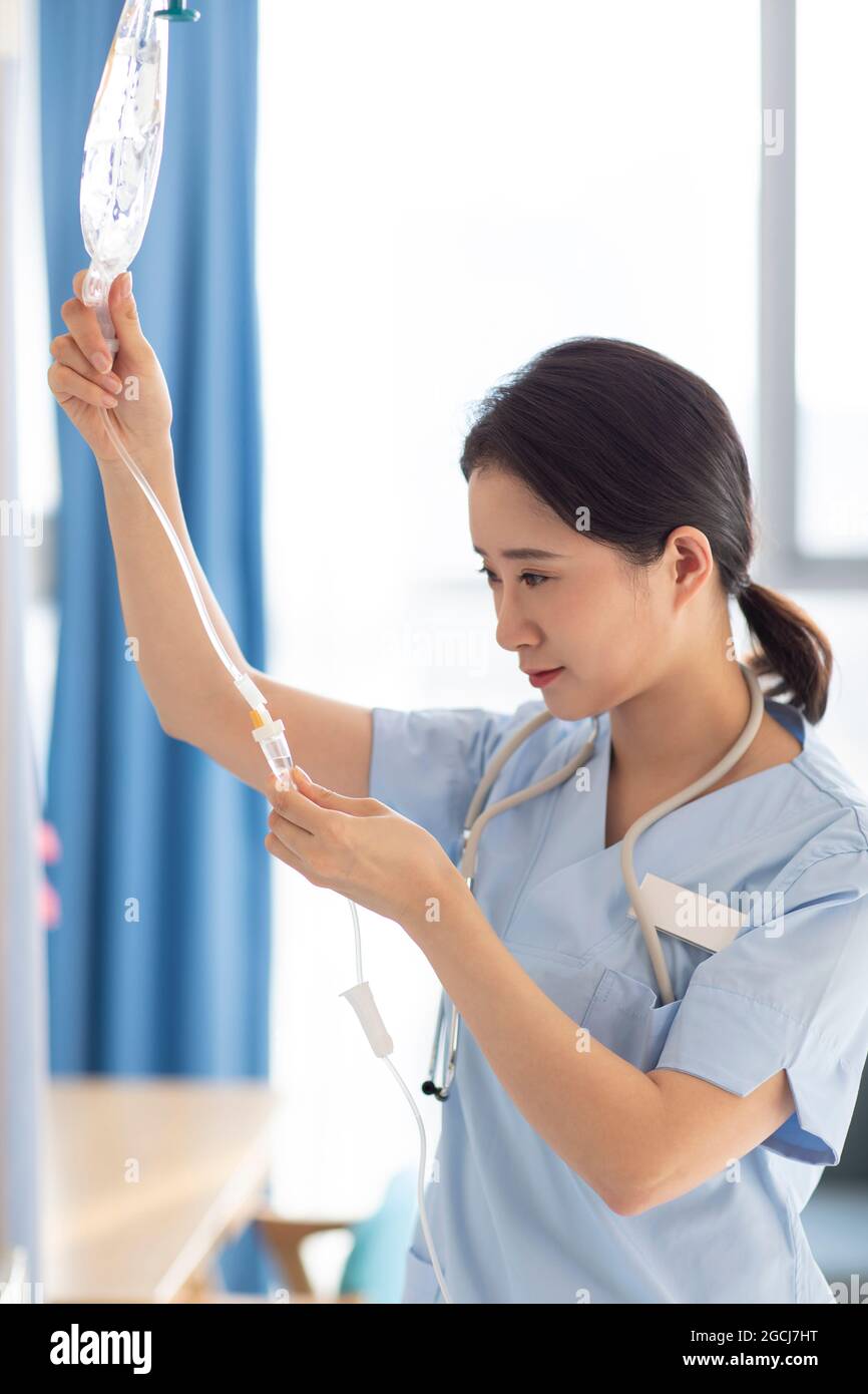 Young nurse checking IV drip in hospital ward Stock Photo - Alamy