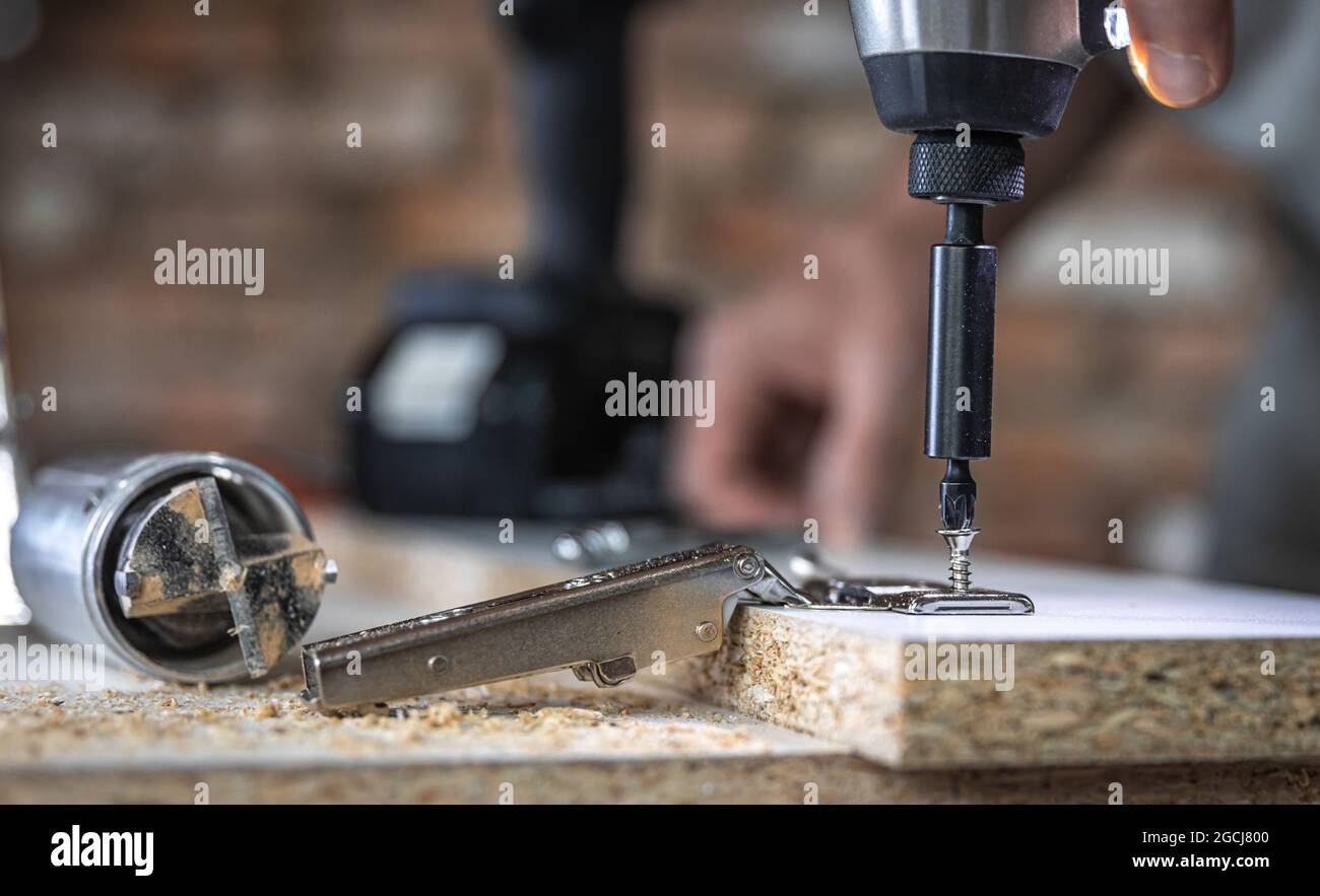 Screwing a self-tapping screw into a metal fastening hole on a wood ...