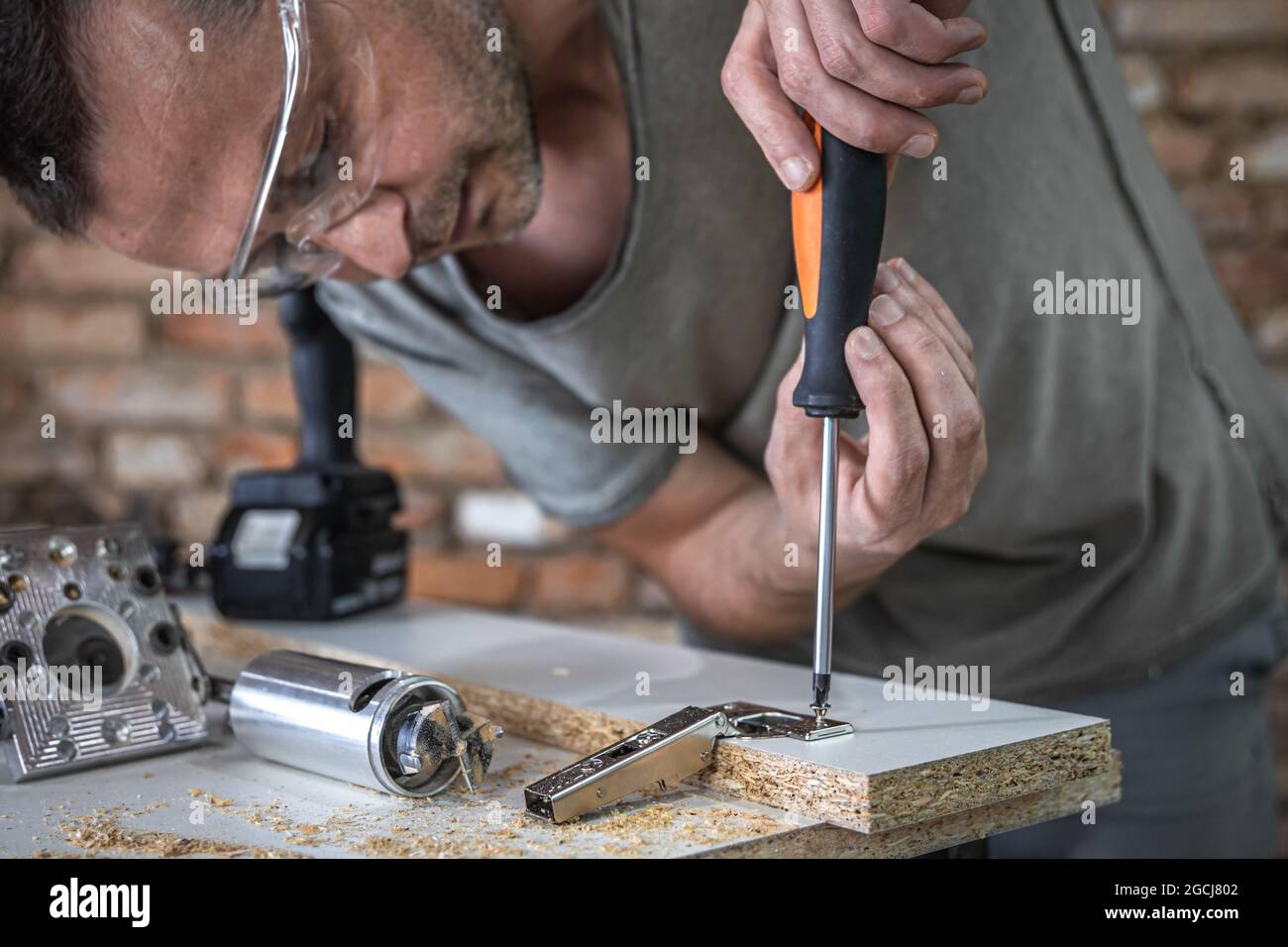 Screwing a self-tapping screw into a metal fastening hole on a wood ...