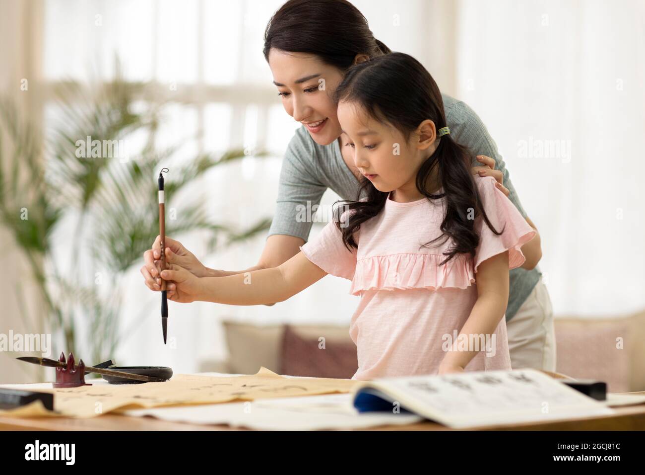 Happy mother and daughter writing calligraphy at home Stock Photo - Alamy