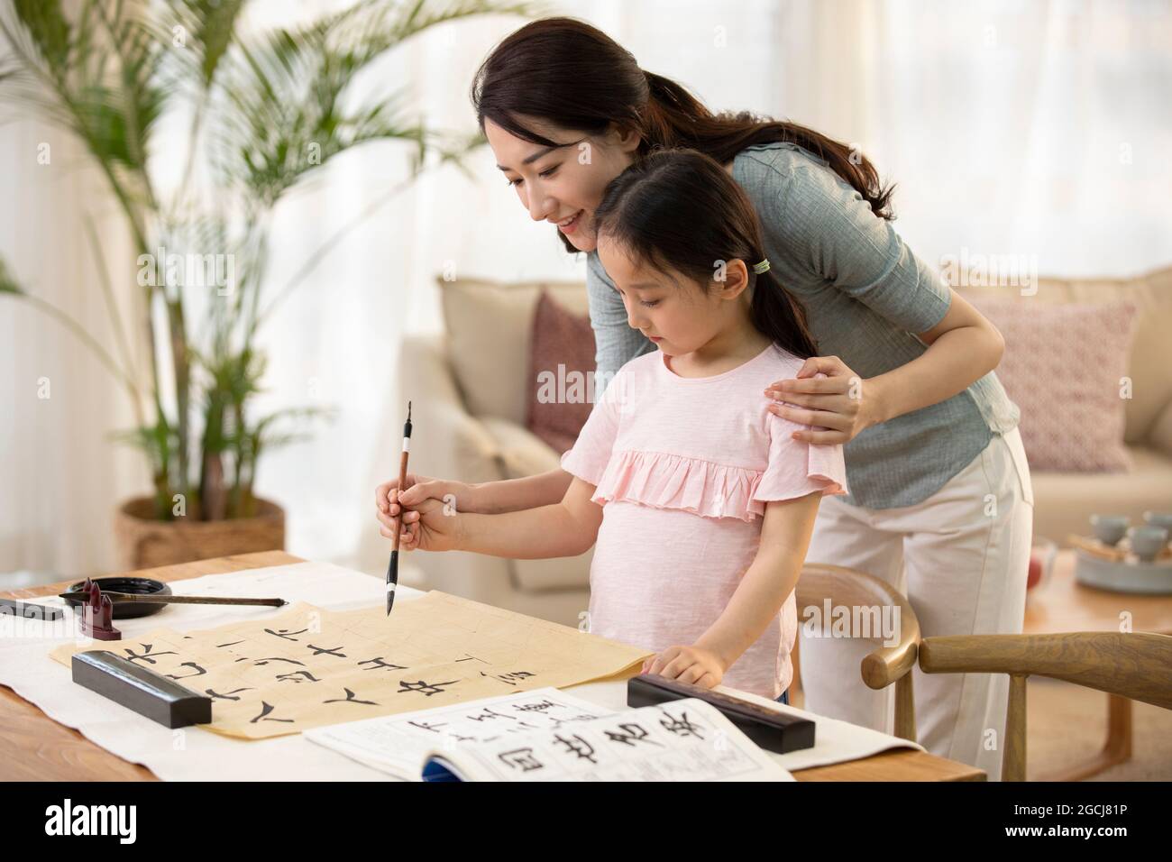 Happy mother and daughter writing calligraphy at home Stock Photo - Alamy