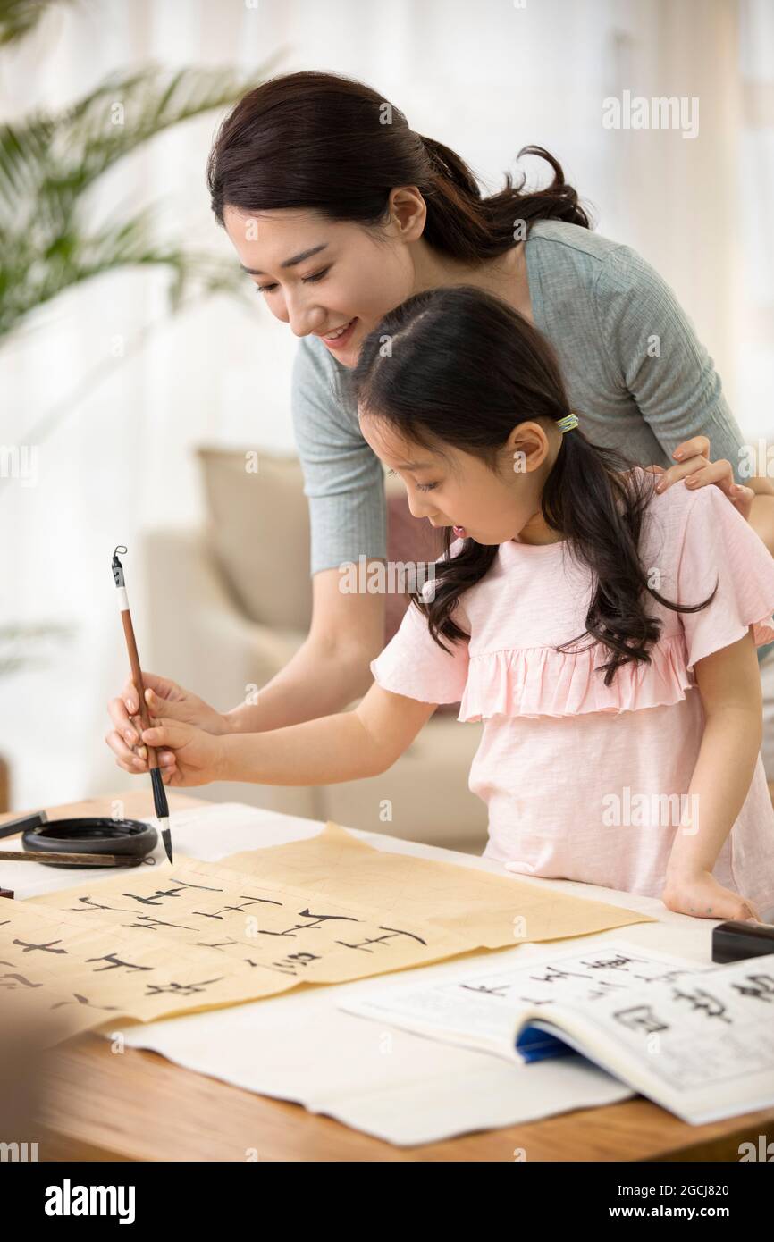 Happy mother and daughter writing calligraphy at home Stock Photo - Alamy