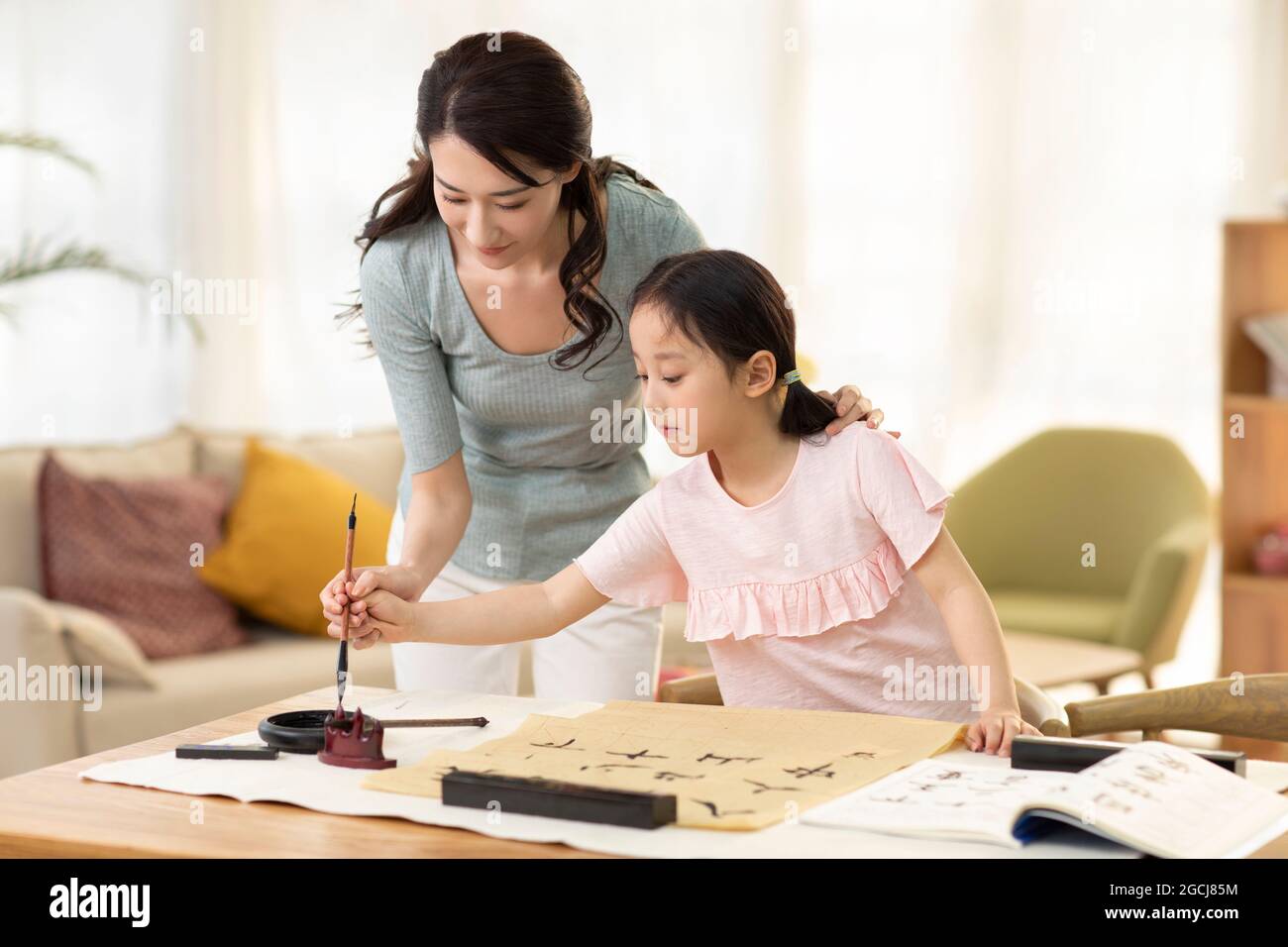 Happy mother and daughter writing calligraphy at home Stock Photo - Alamy