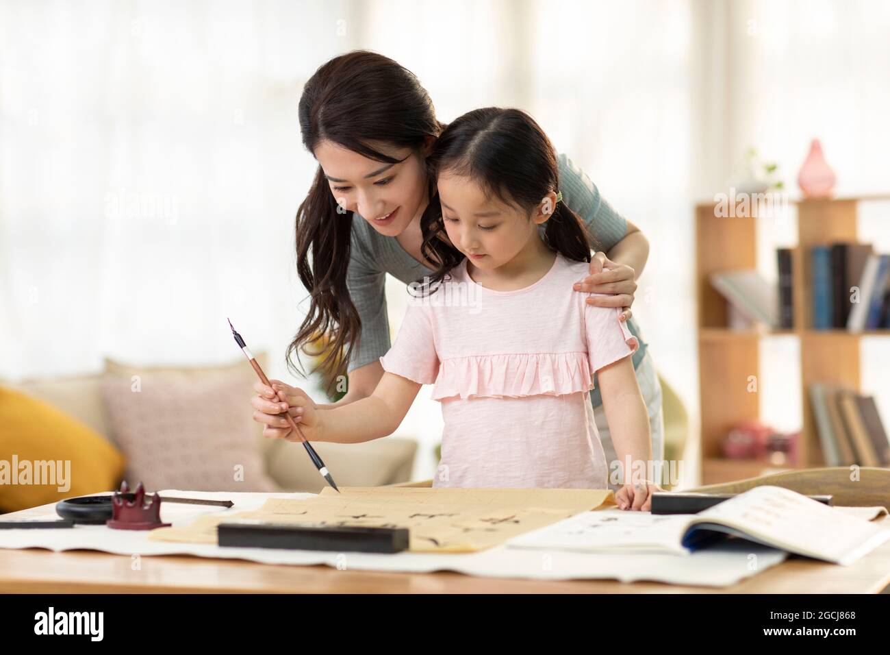 Happy mother and daughter writing calligraphy at home Stock Photo - Alamy