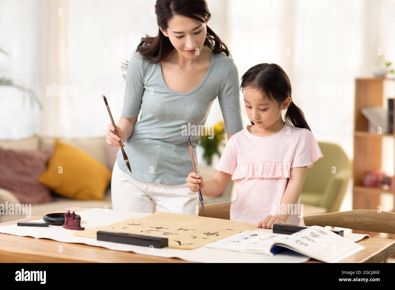 Happy mother and daughter writing calligraphy at home Stock Photo - Alamy