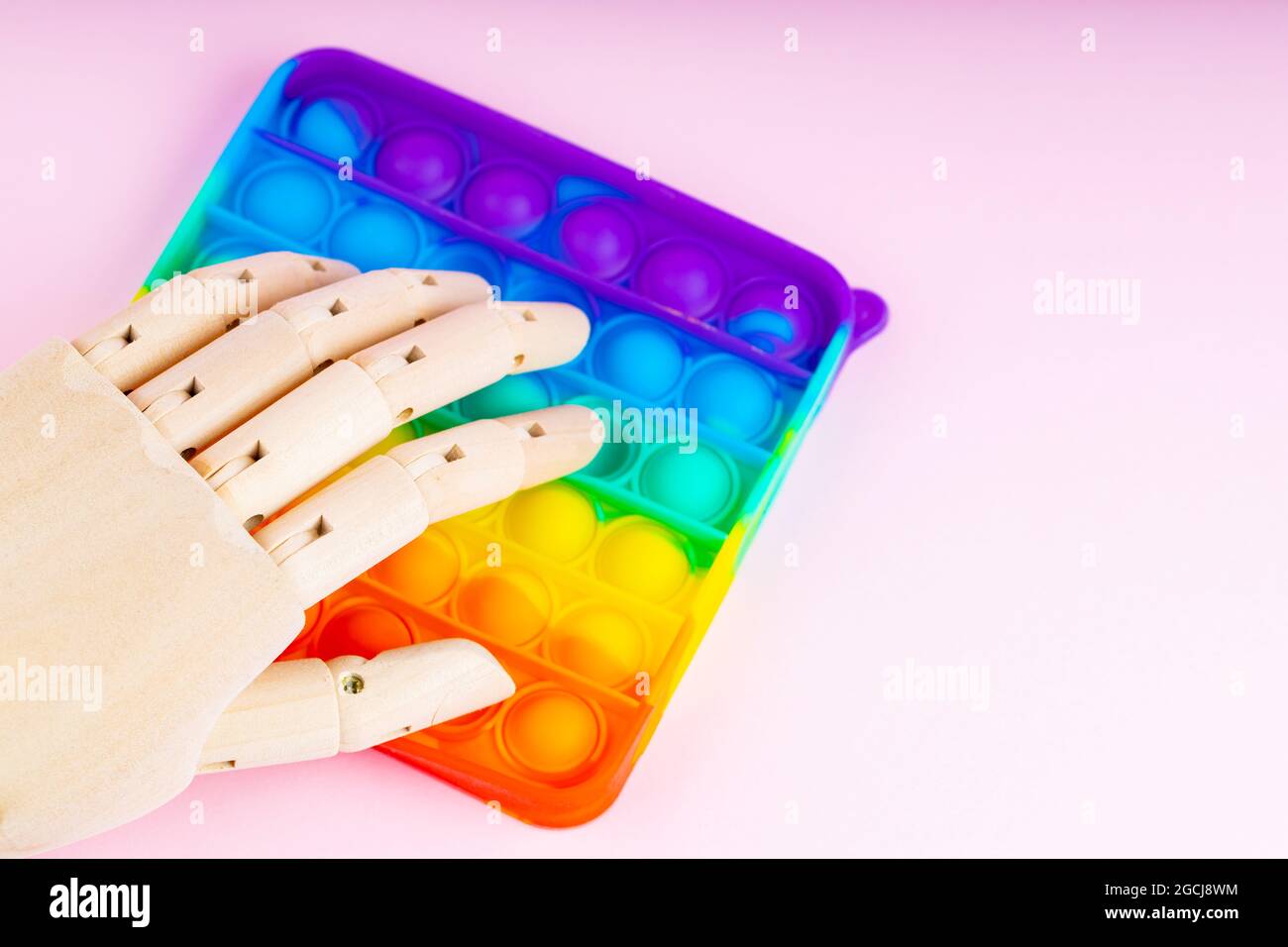 Pop it toy and artificial hand on pink background. Robot clicks on pop ...