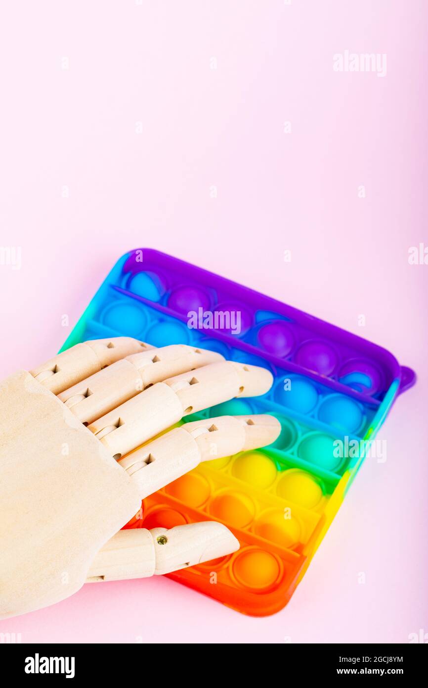 Pop it toy and artificial hand on pink background. Robot clicks on pop ...