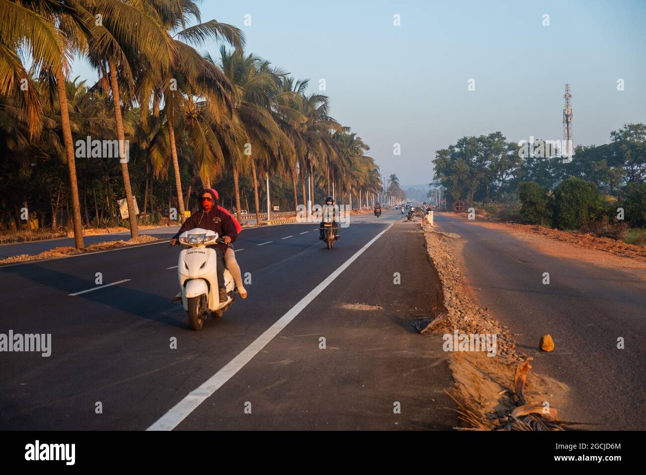 Morning Road Amidst Trees with motorcyclists, Goa, India Stock Photo ...