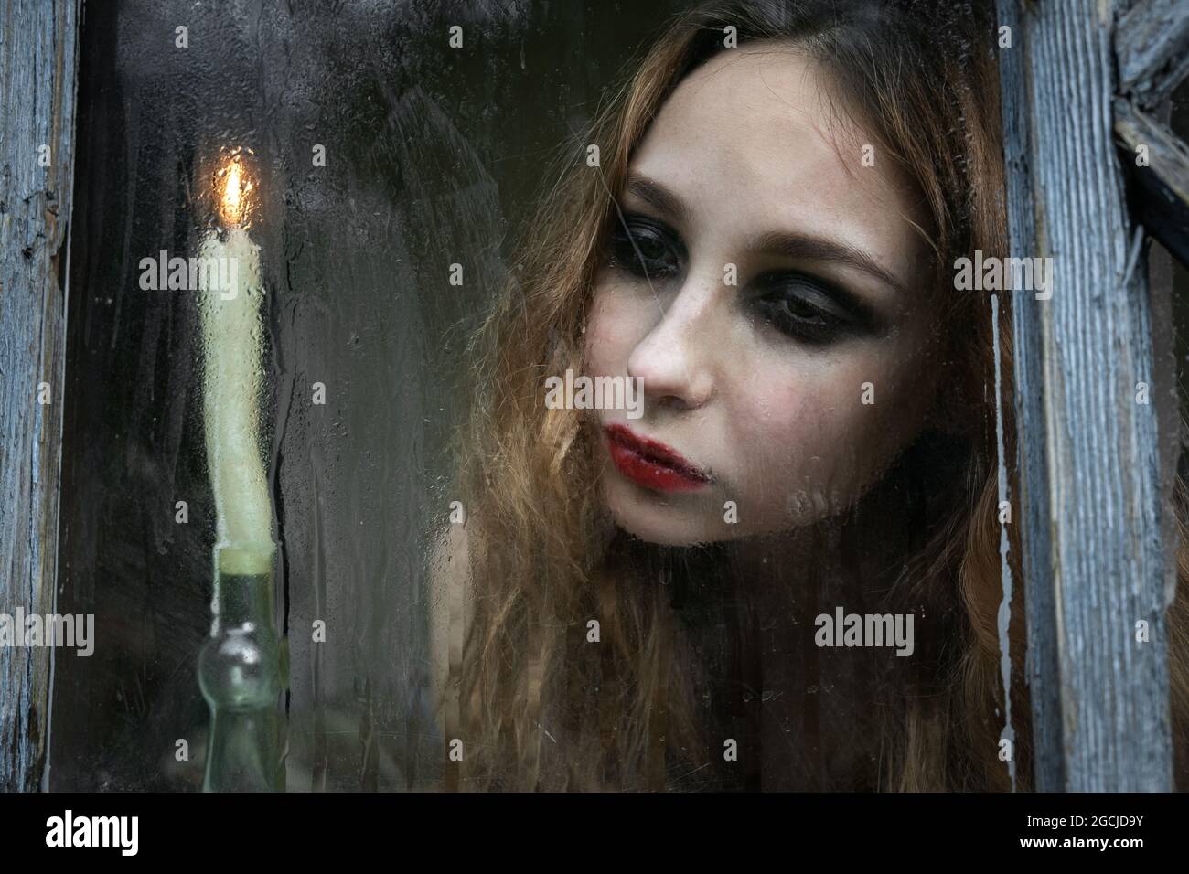 Beautiful Sad Young Girl Looking Out The Window With A Candle Good For