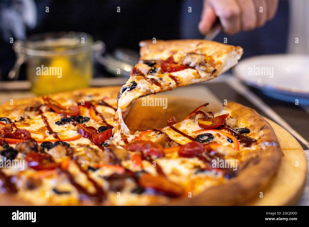 Hand of man holding slice of pizza over the table against restaurant ...
