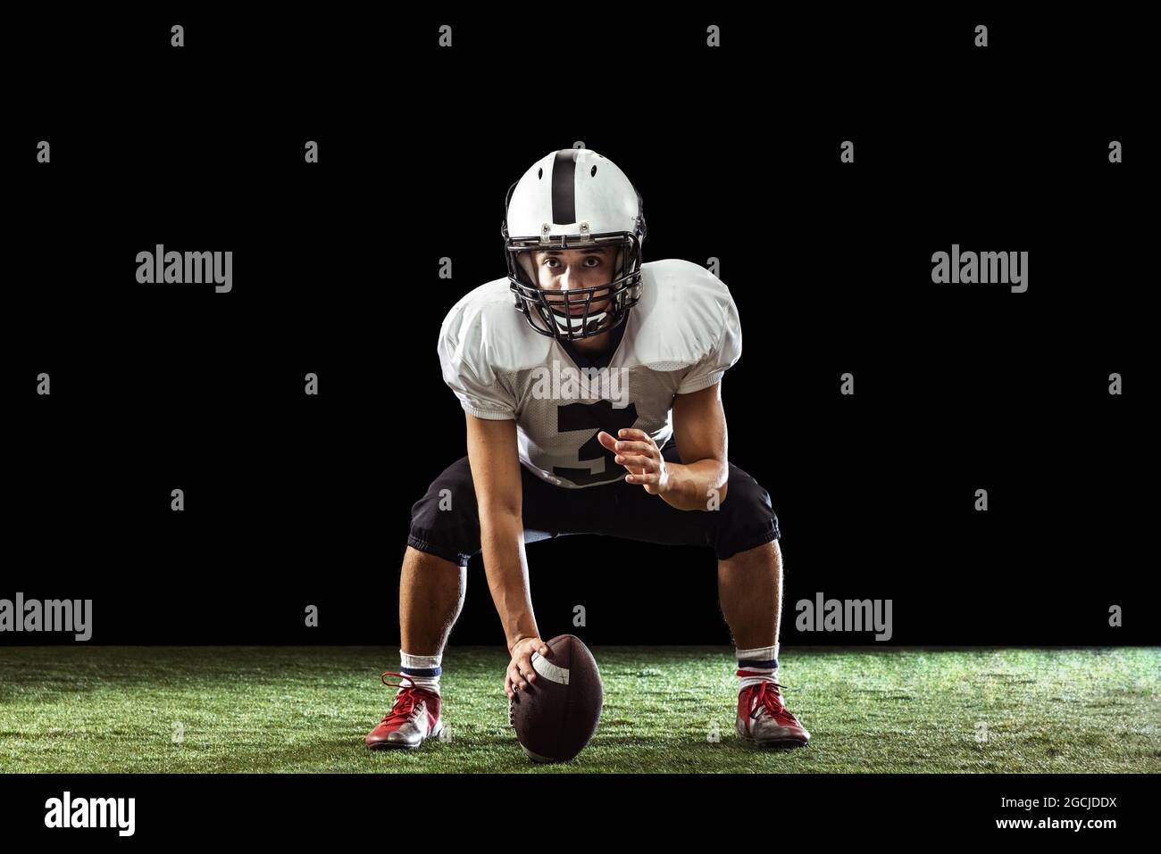 Portrait of American football player training isolated on dark studio ...