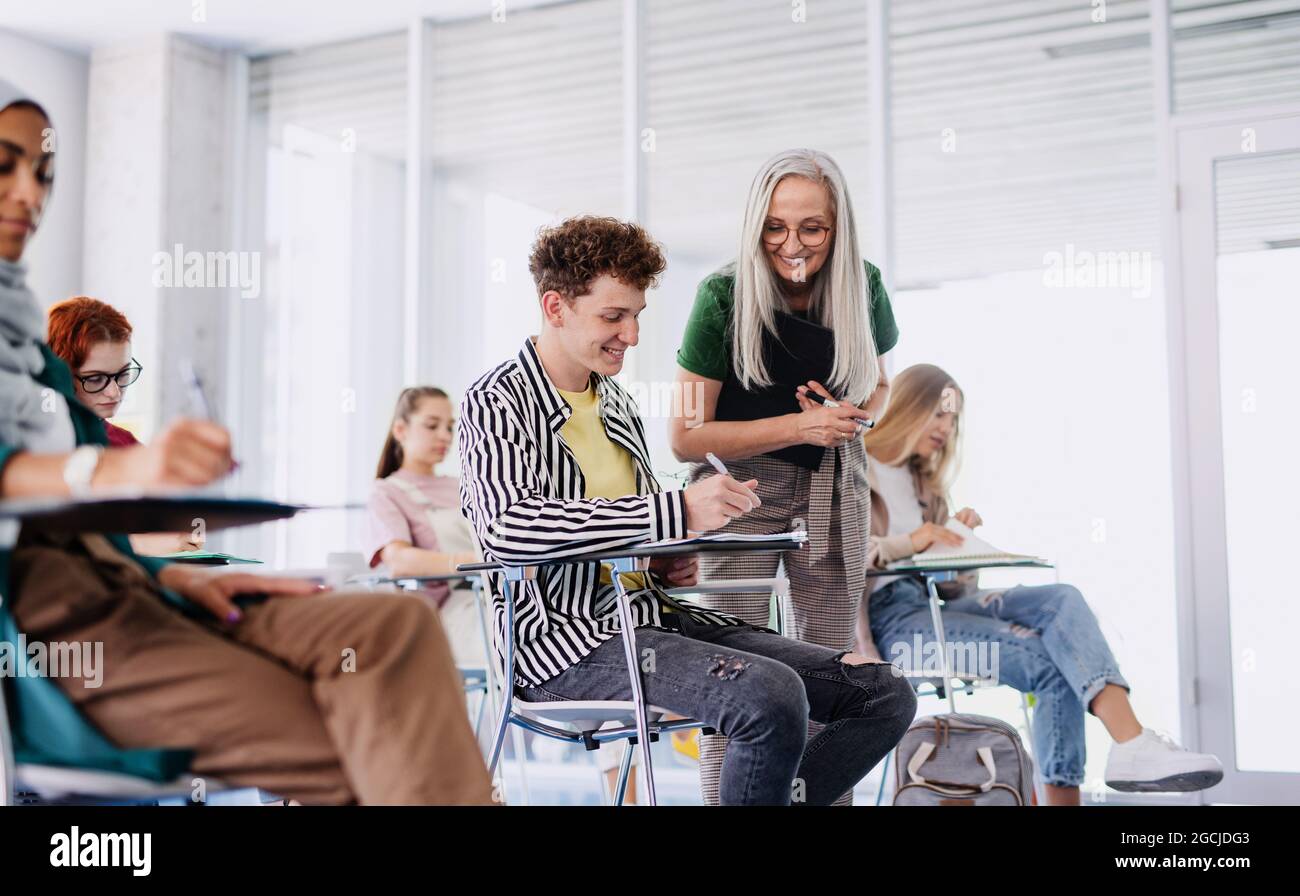 University students with teacher studying indoors, lesson in classroom ...