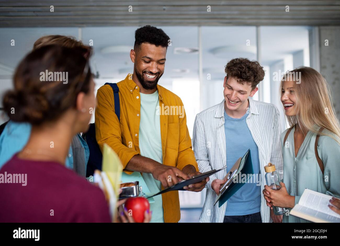 Group of university students standing in corridor indoors, talking ...
