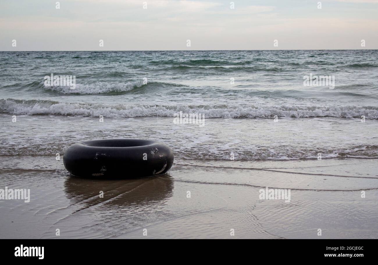 Black swim ring on the beach in the evening. Rubber ring floating in ...