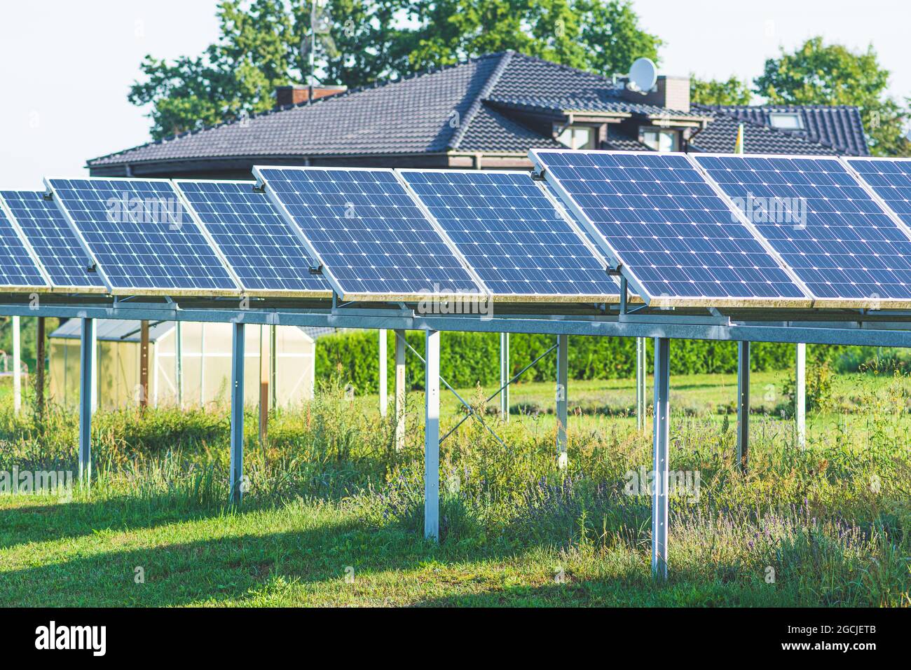 Solar panels on the field in the countryside with house on background ...