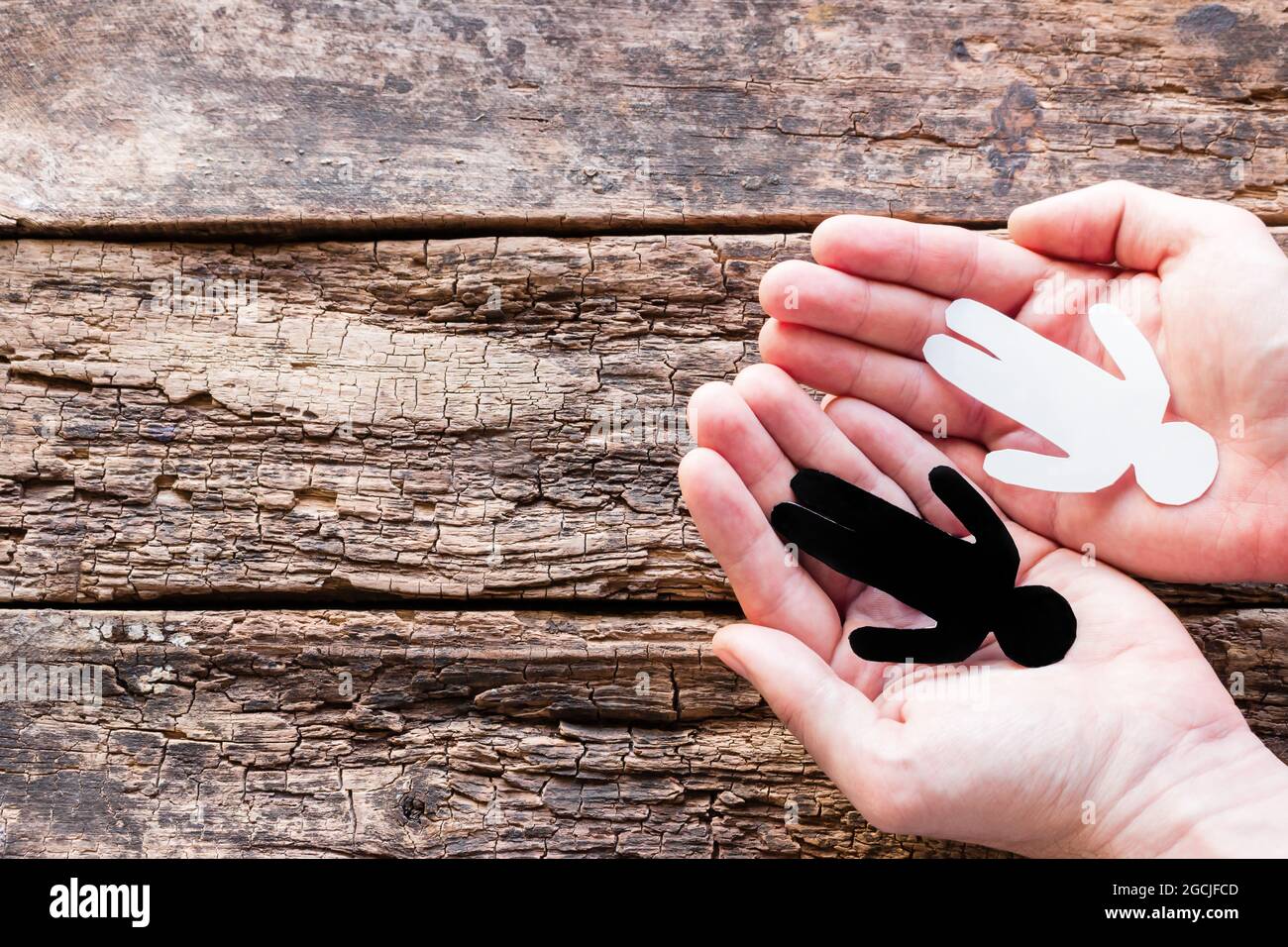 holding black and white silhouettes on wooden background with place for ...