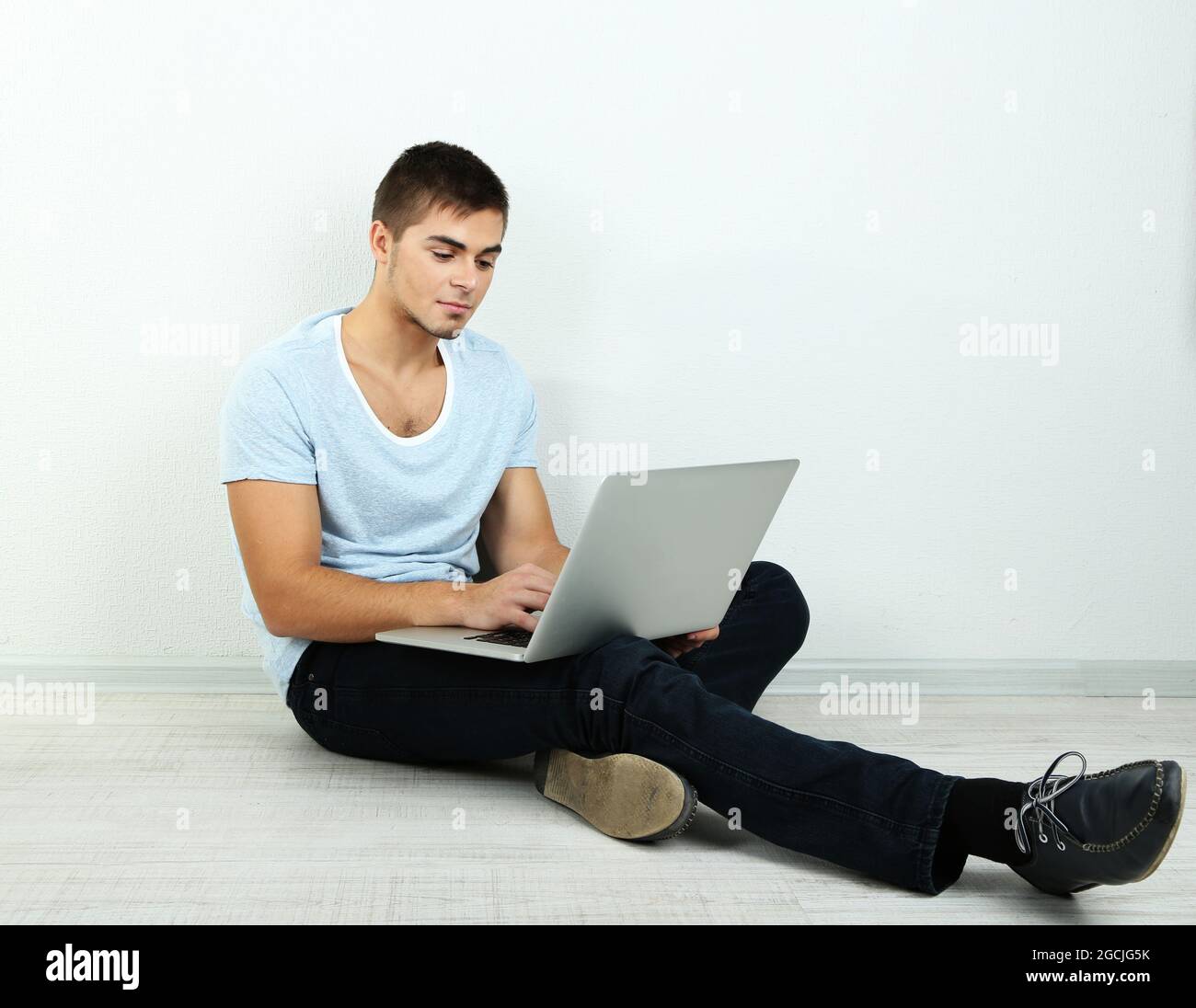 Guy sitting on floor in room Stock Photo - Alamy