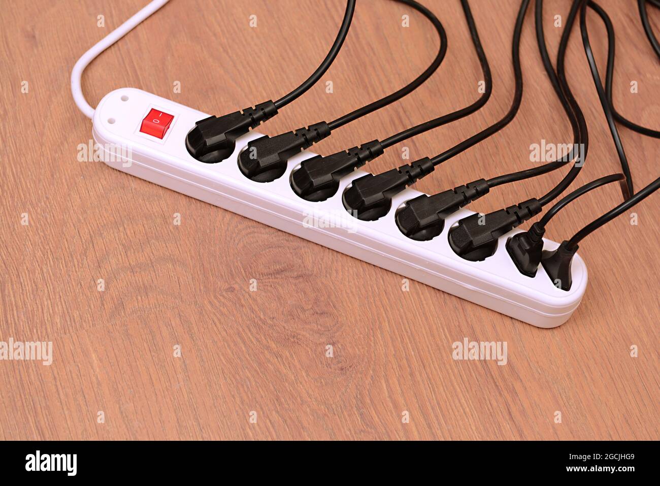 Overloaded power board, on wooden floor background Stock Photo - Alamy
