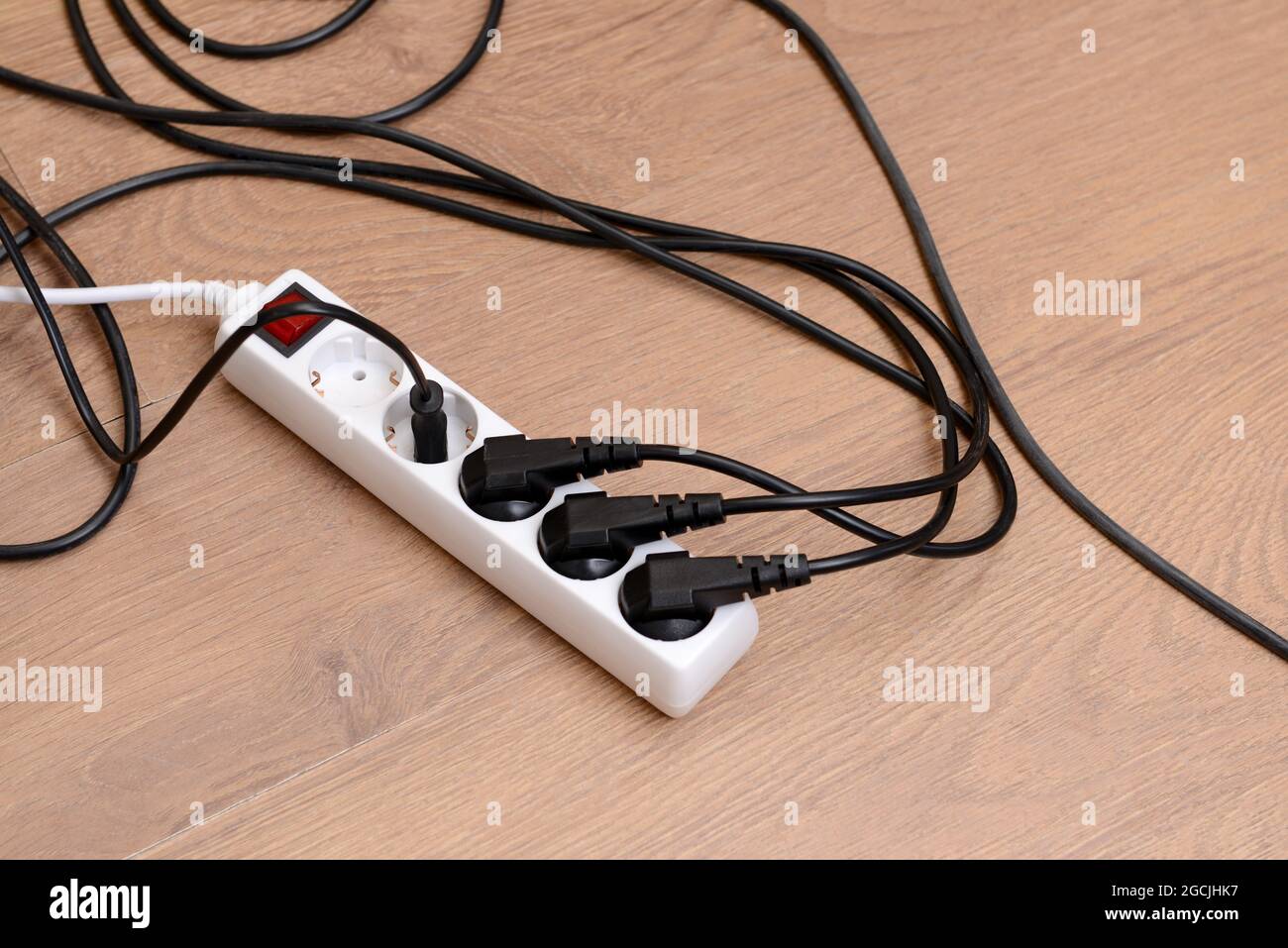 Overloaded power board, on wooden floor background Stock Photo - Alamy