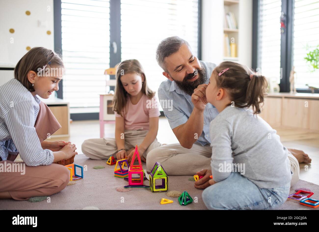 Father With Three Daughters Indoors At Home Playing On Floor Stock