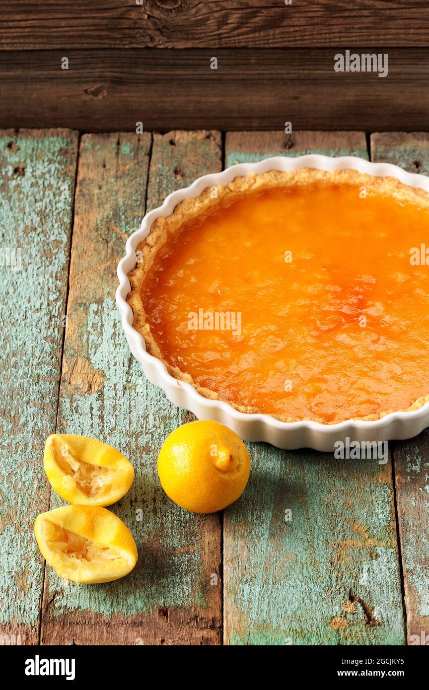 Open lemon pie and squeezed lemons on shabby old wooden boards vertical ...
