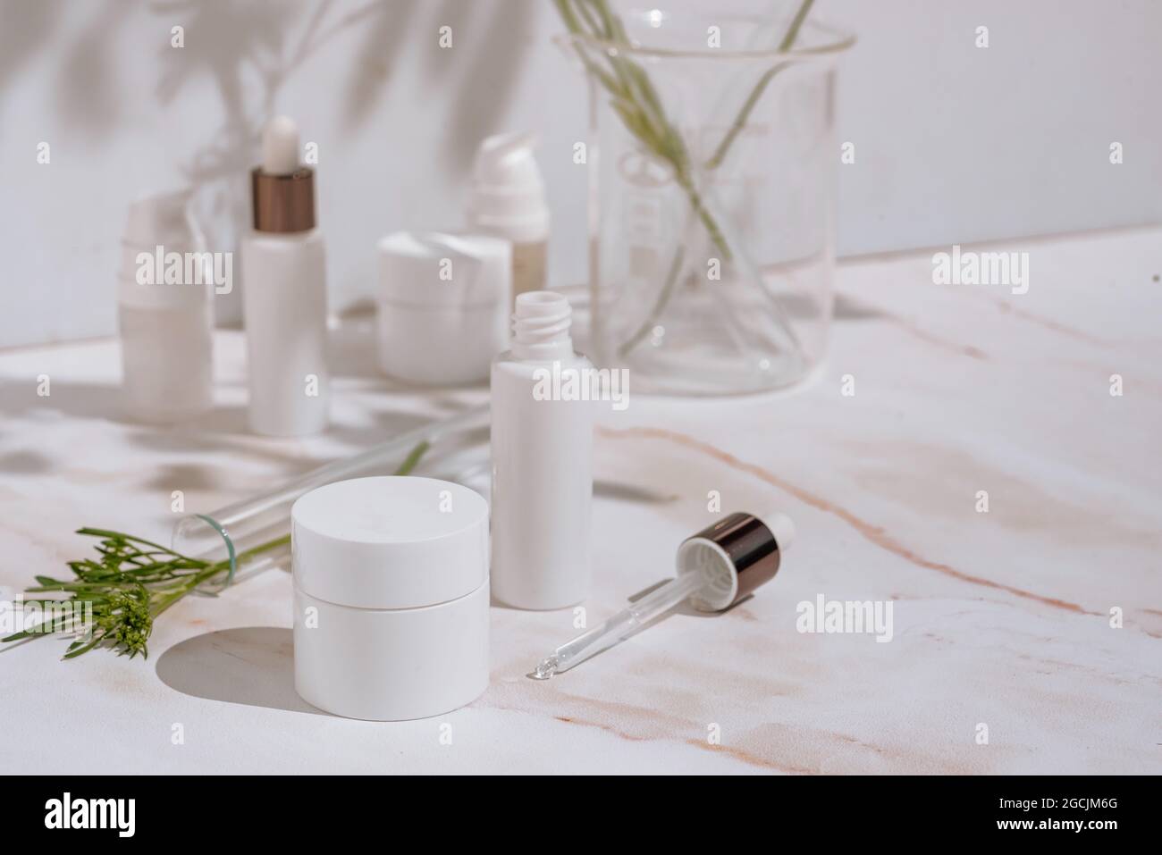 Natural cosmetic products in white packaging with laboratory glassware ...