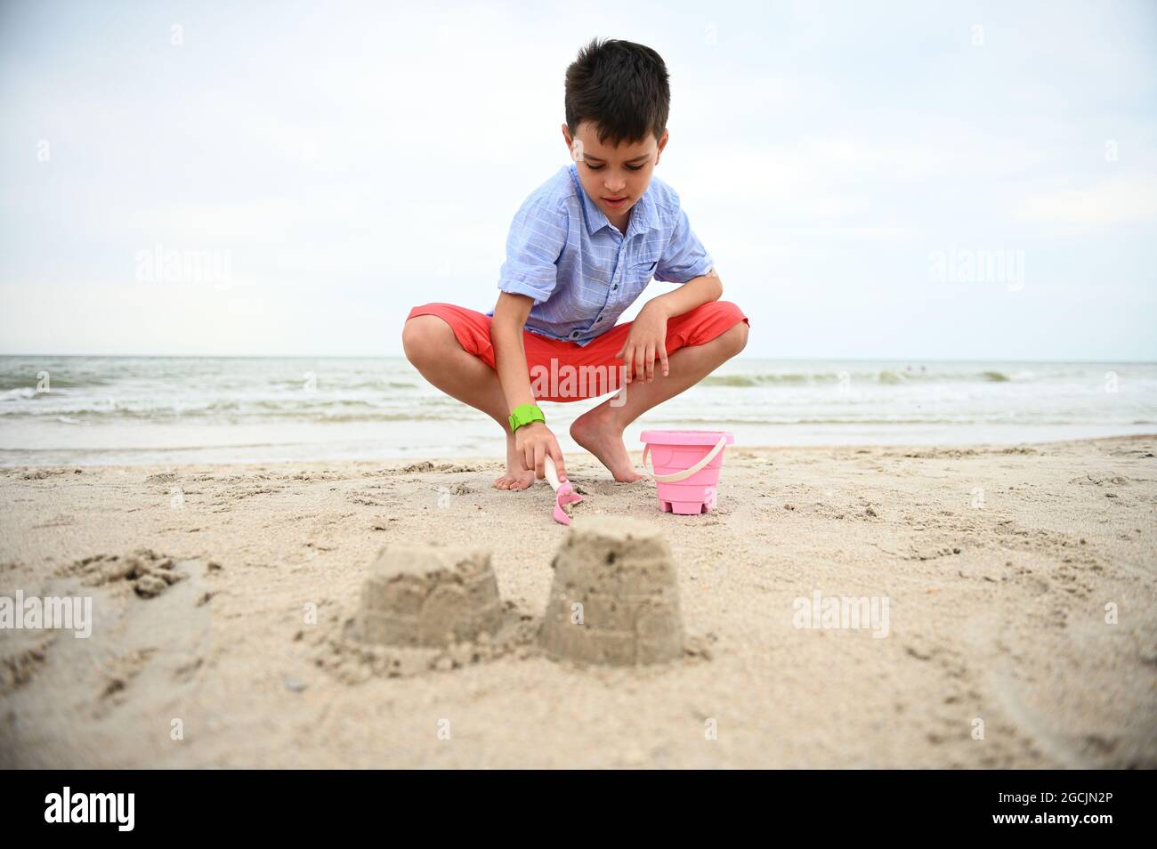 Happy, handsome and adorable boy, child, toddler filling toy bucket ...
