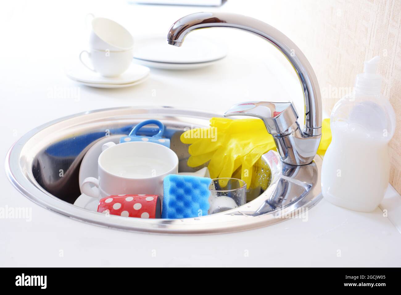 Stack of dishes soaking in kitchen sink Stock Photo - Alamy