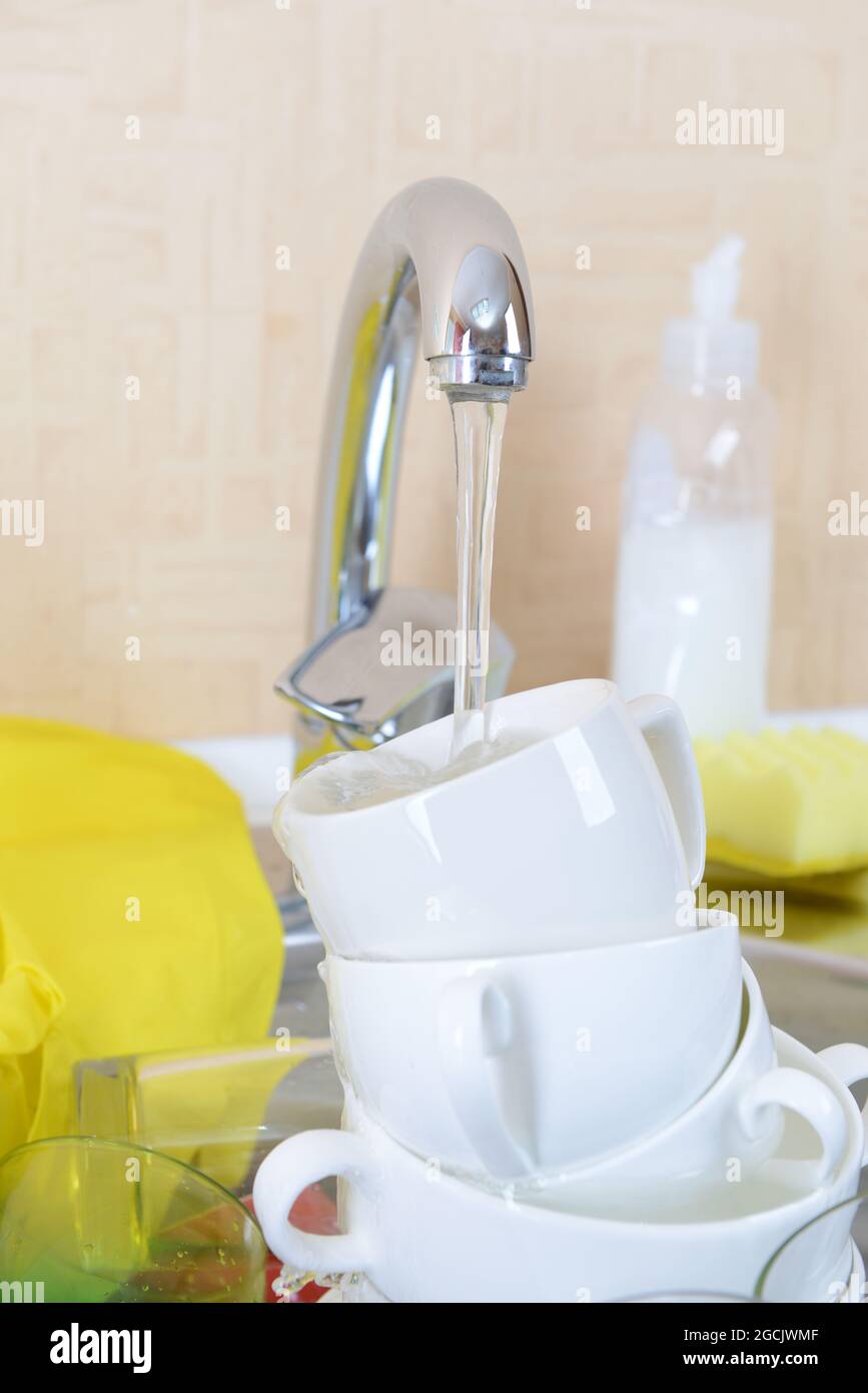 Stack of dishes soaking in kitchen sink Stock Photo - Alamy