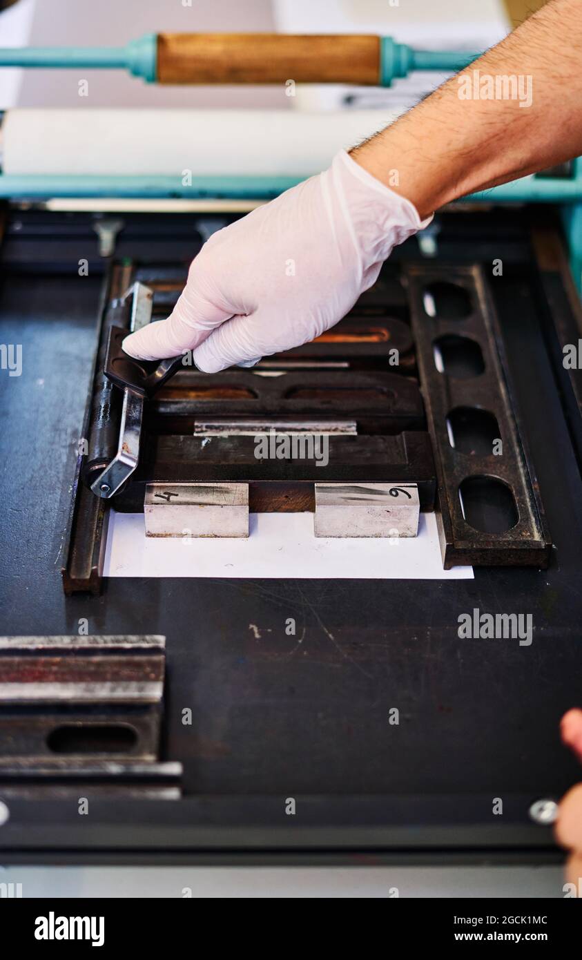 Crop unrecognizable craftsman making imprint of metal letters on paper ...