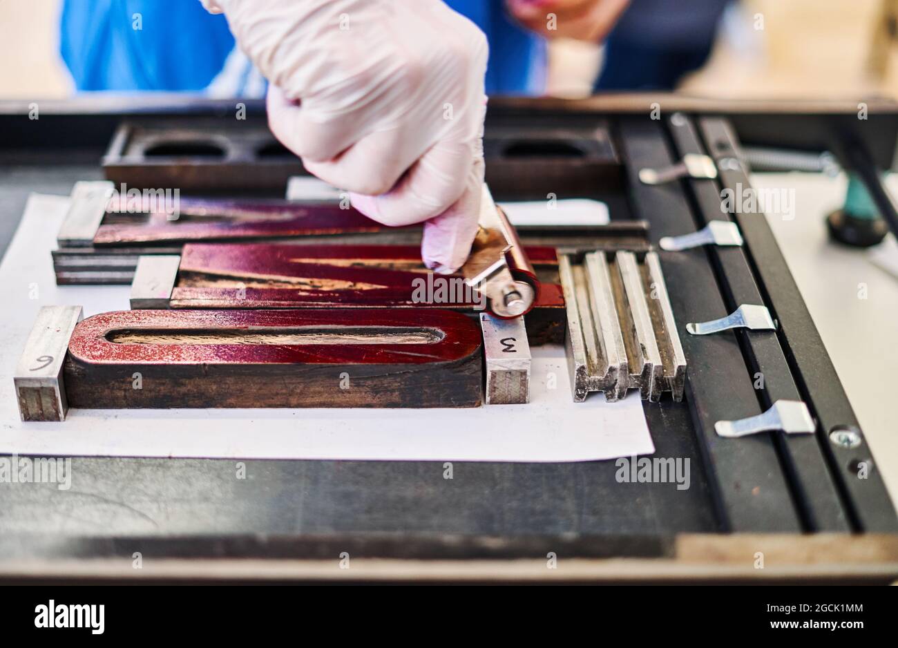 Crop unrecognizable male worker painting letterpress font with roller ...