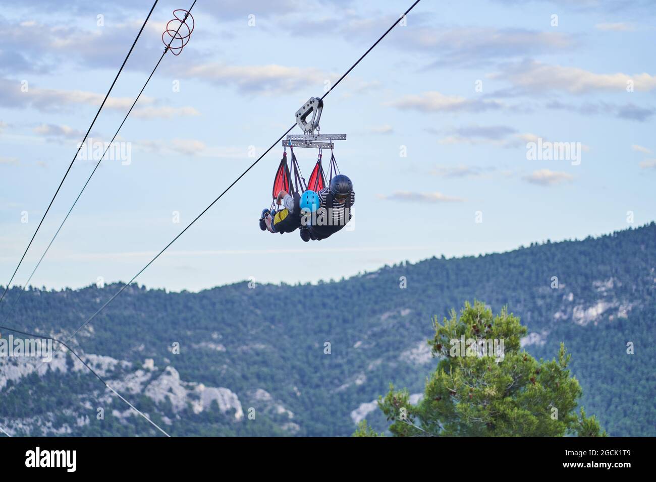 Anonymous brave people in safety equipment riding zip line over ...