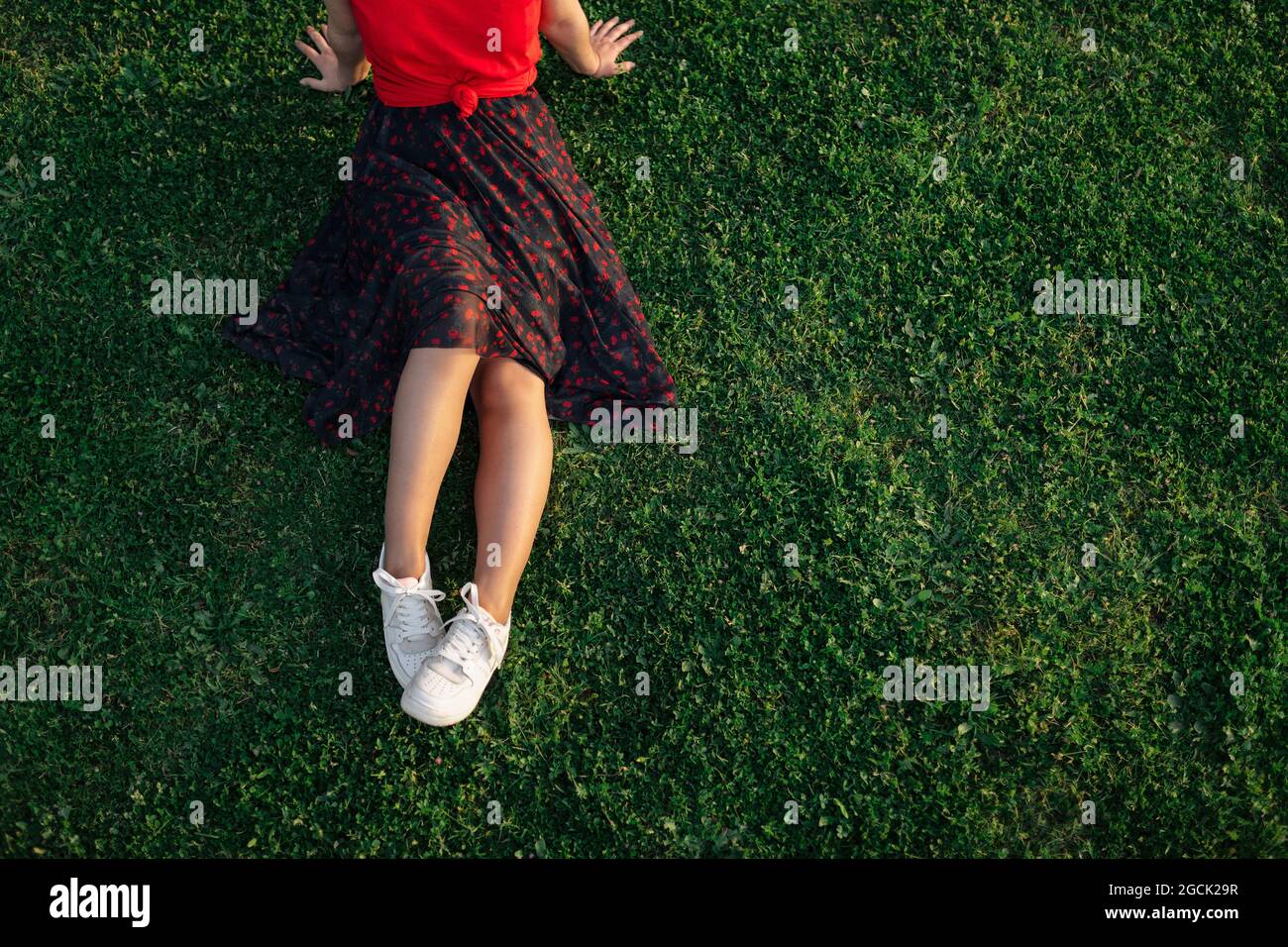 crop Tranquil female sitting on grass on meadow in park and enjoy ...